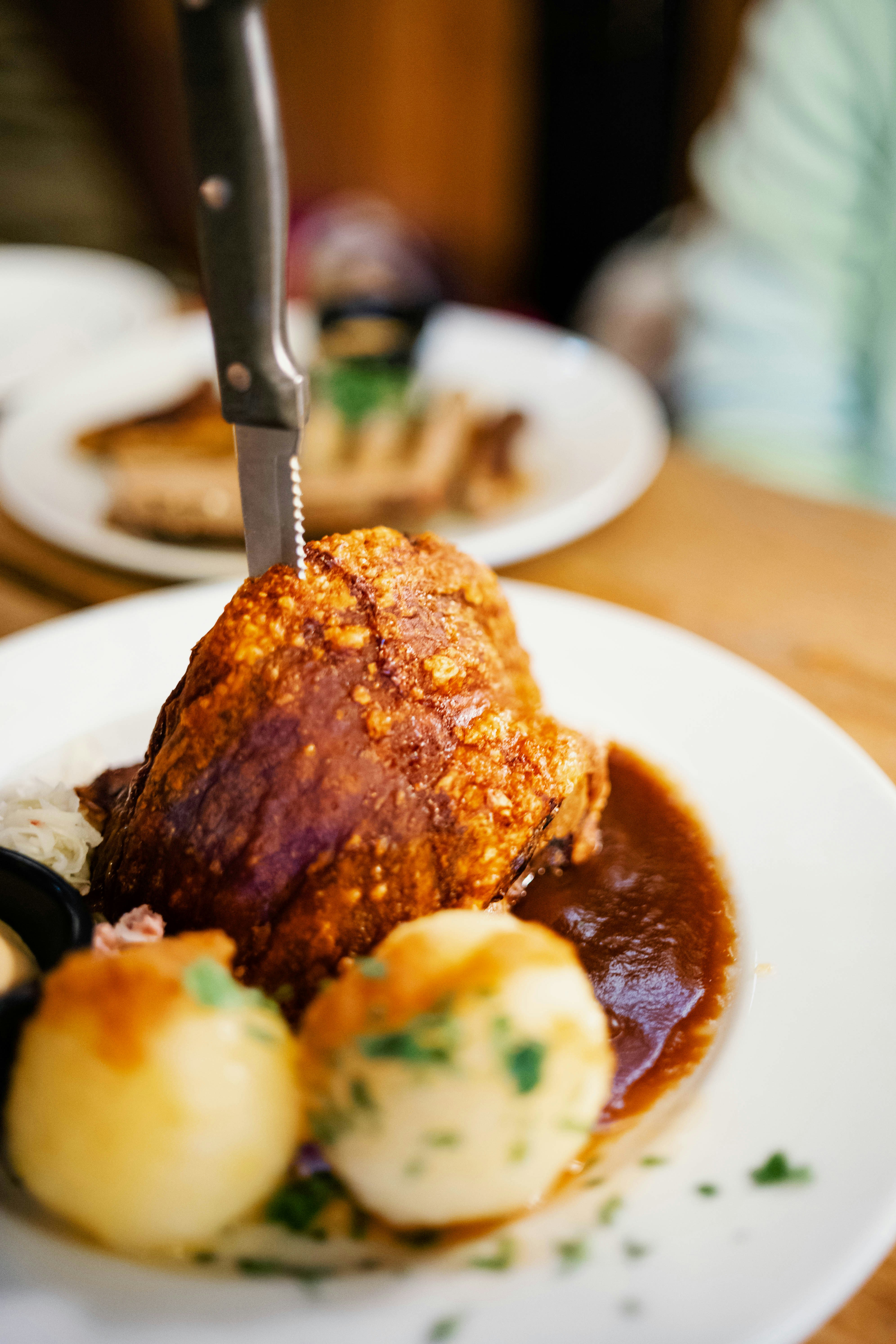 Crisped roast with gravy and potatoes, captured mid-cut at the table