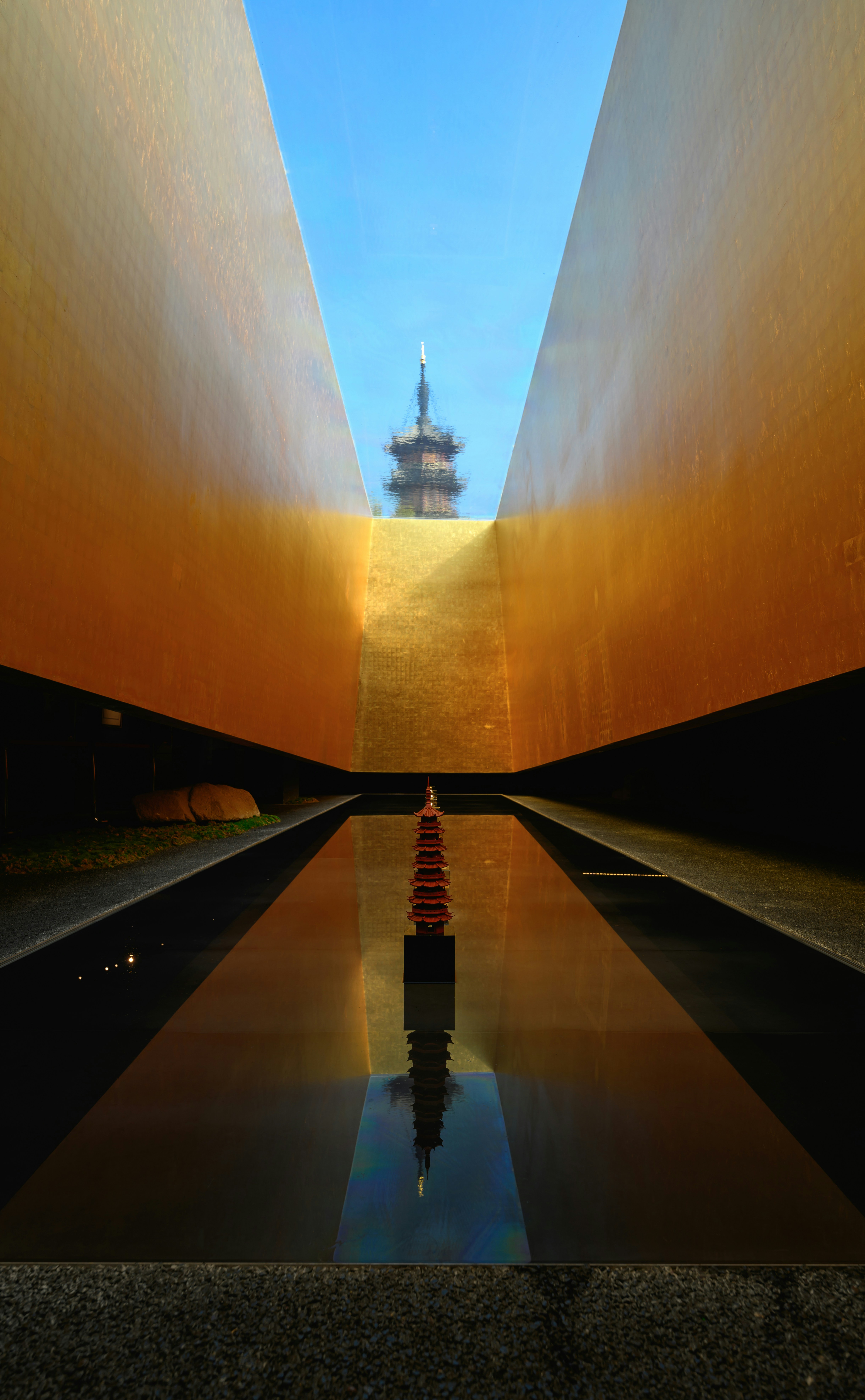 Golden Corridor Framing a Red-Topped Spire, Reflected in a Narrow Pool