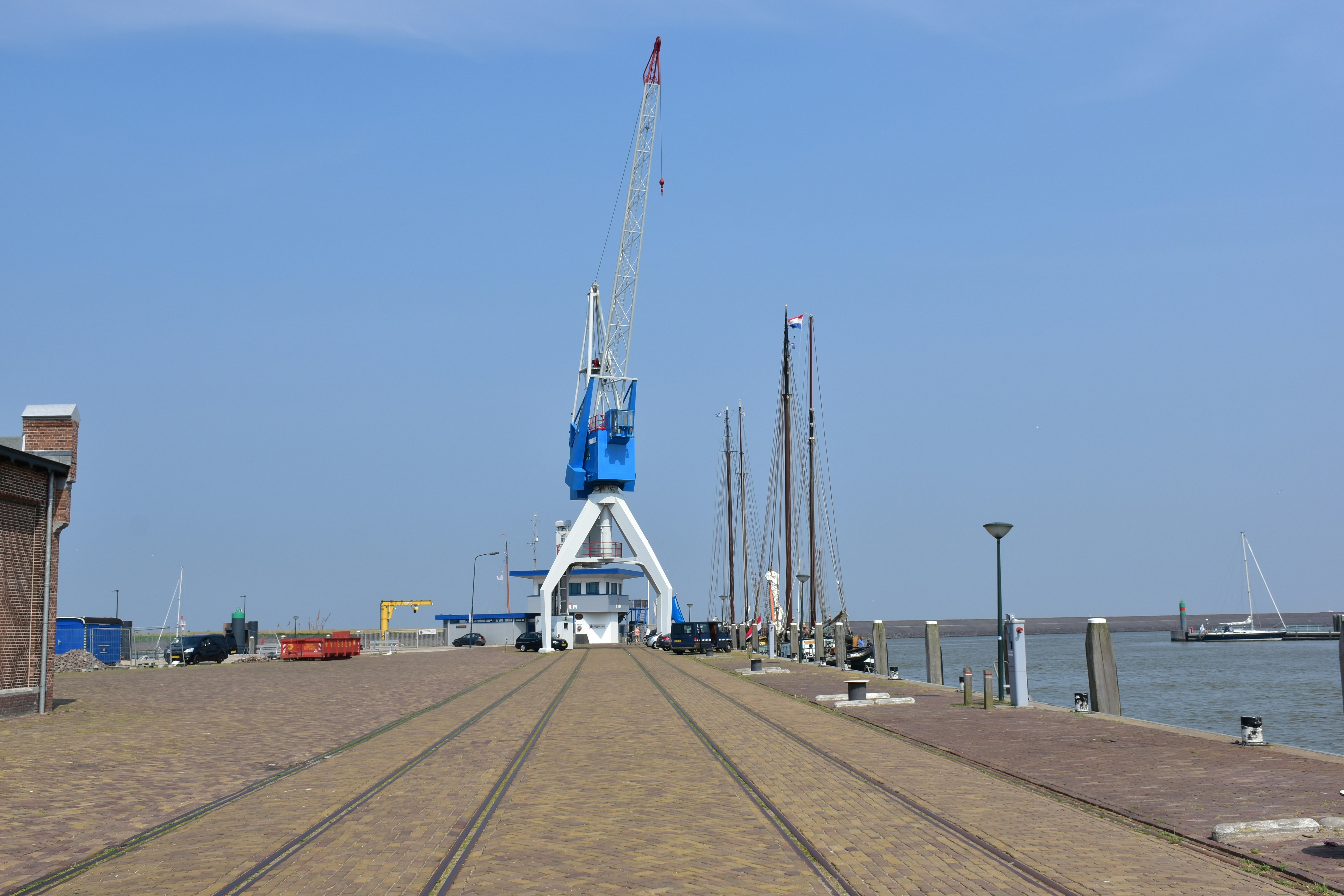 Blue Crane at the Promenade: Rails Stretch Toward the Harbor