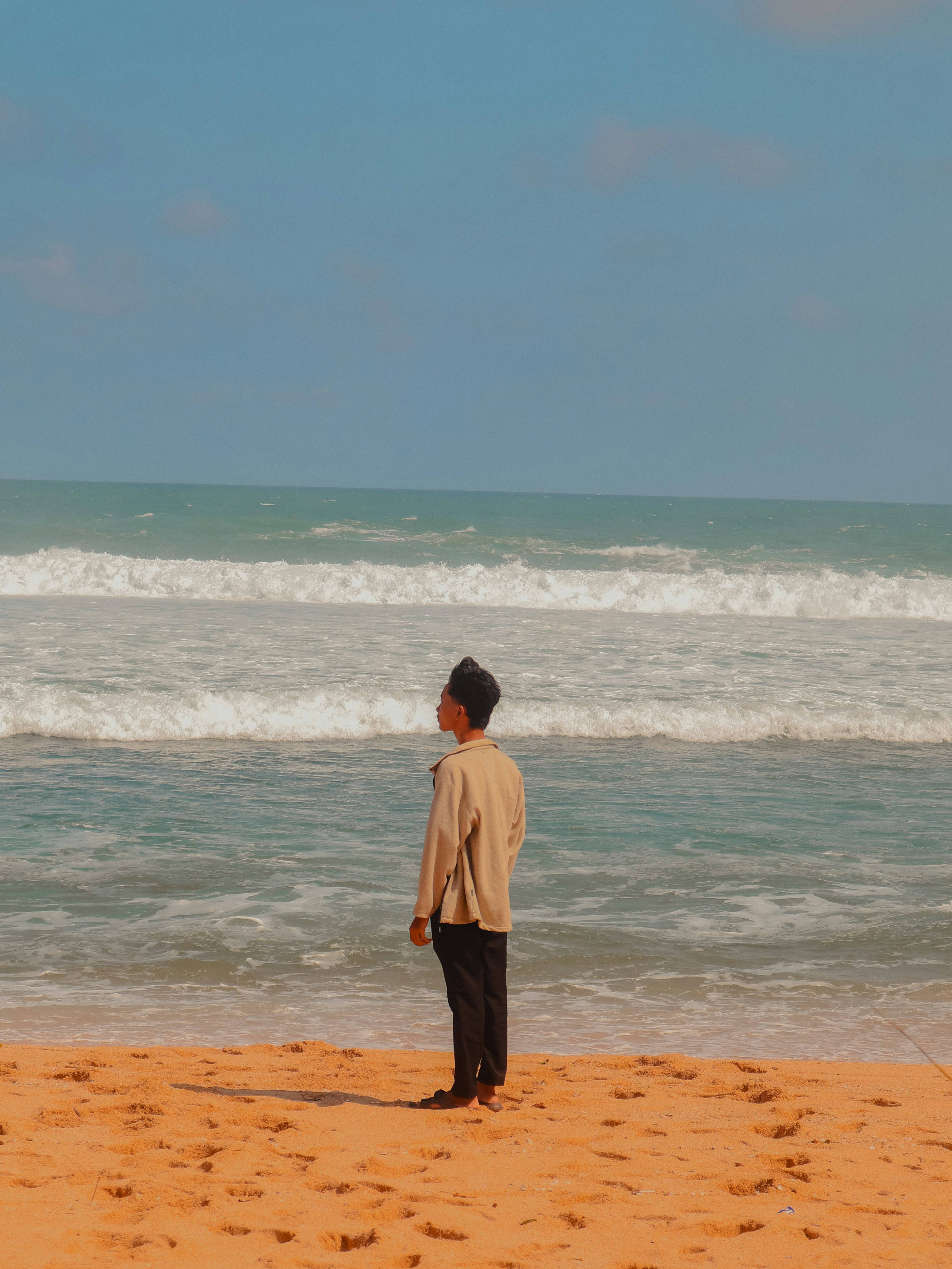 Lone Figure on the Shoreline: A Quiet Contemplation Among Rolling Surf