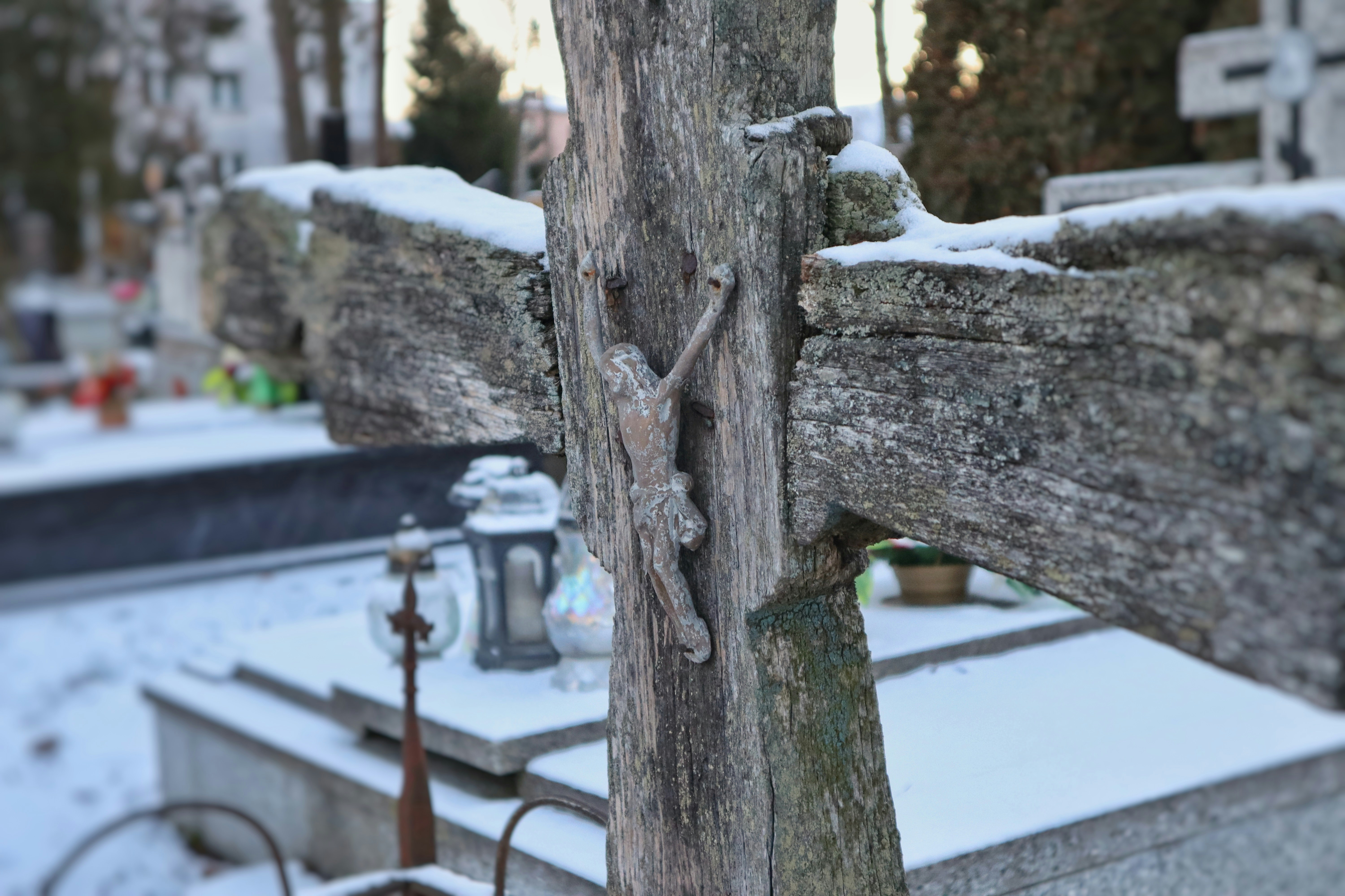 Weathered Crucifix on Frost-Kissed Timber in a Snowbound Cemetery