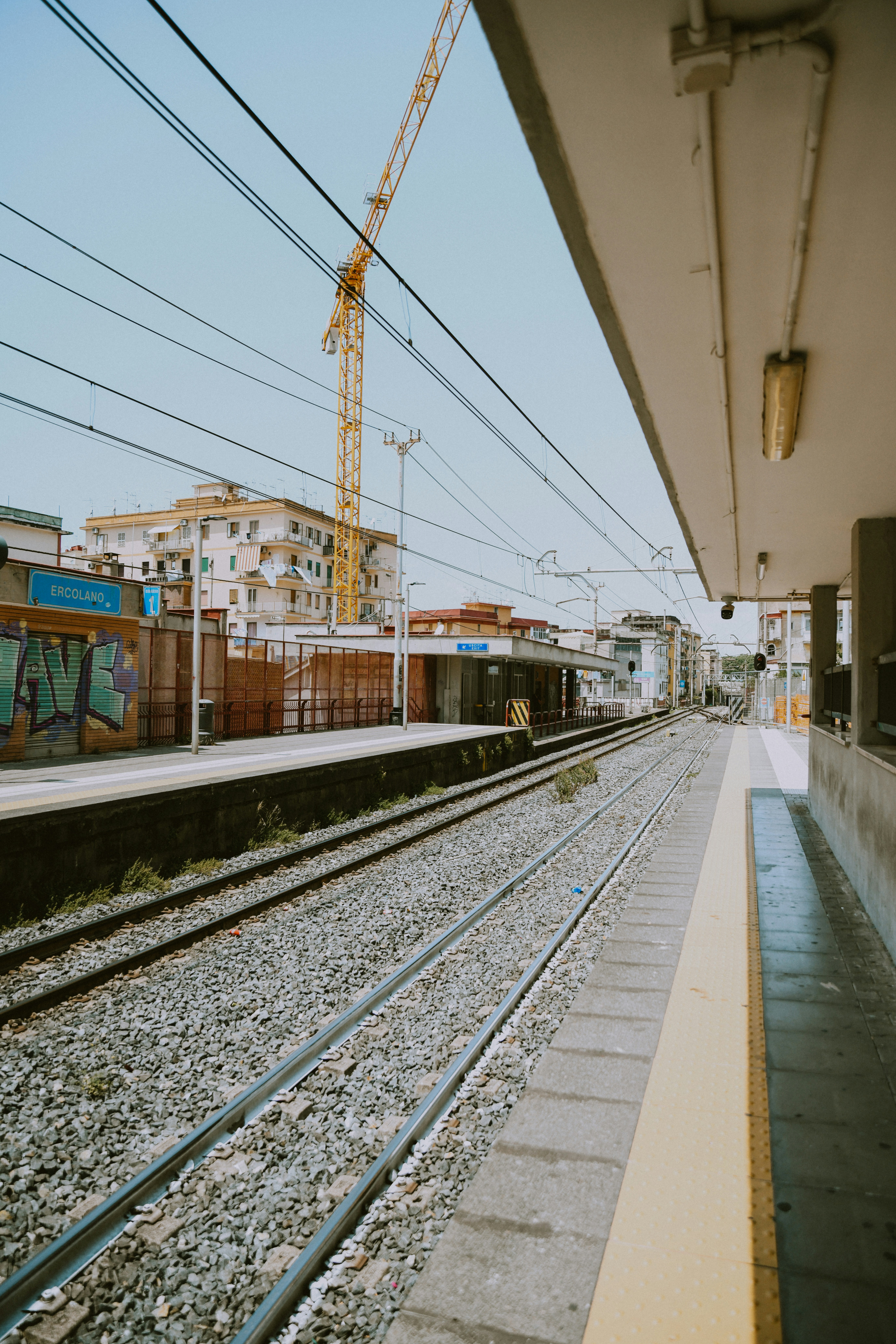 Crane silhouette over a sunlit city rail platform
