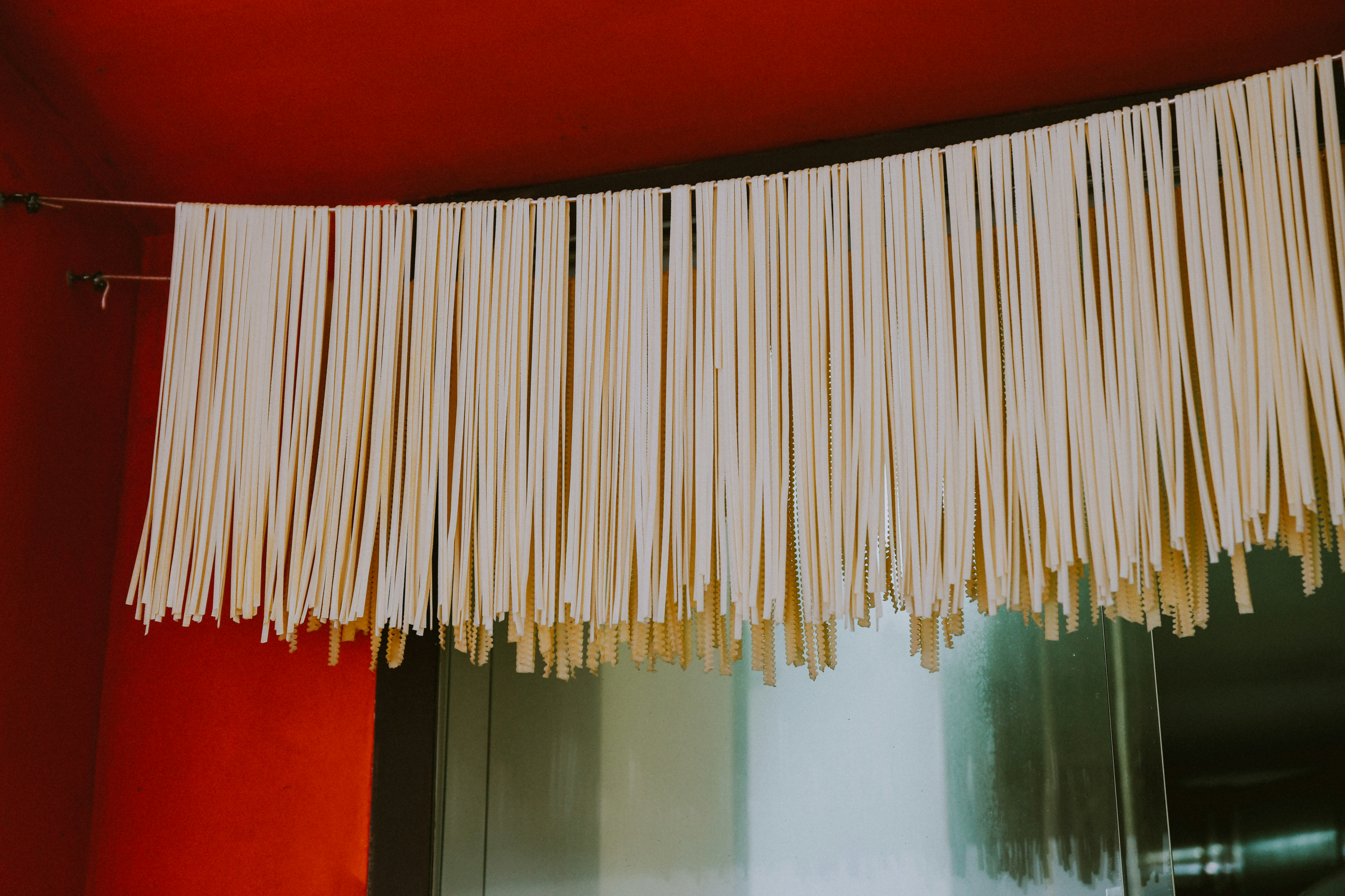 A close up of a red wall with a bunch of noodles hanging from it photo ...
