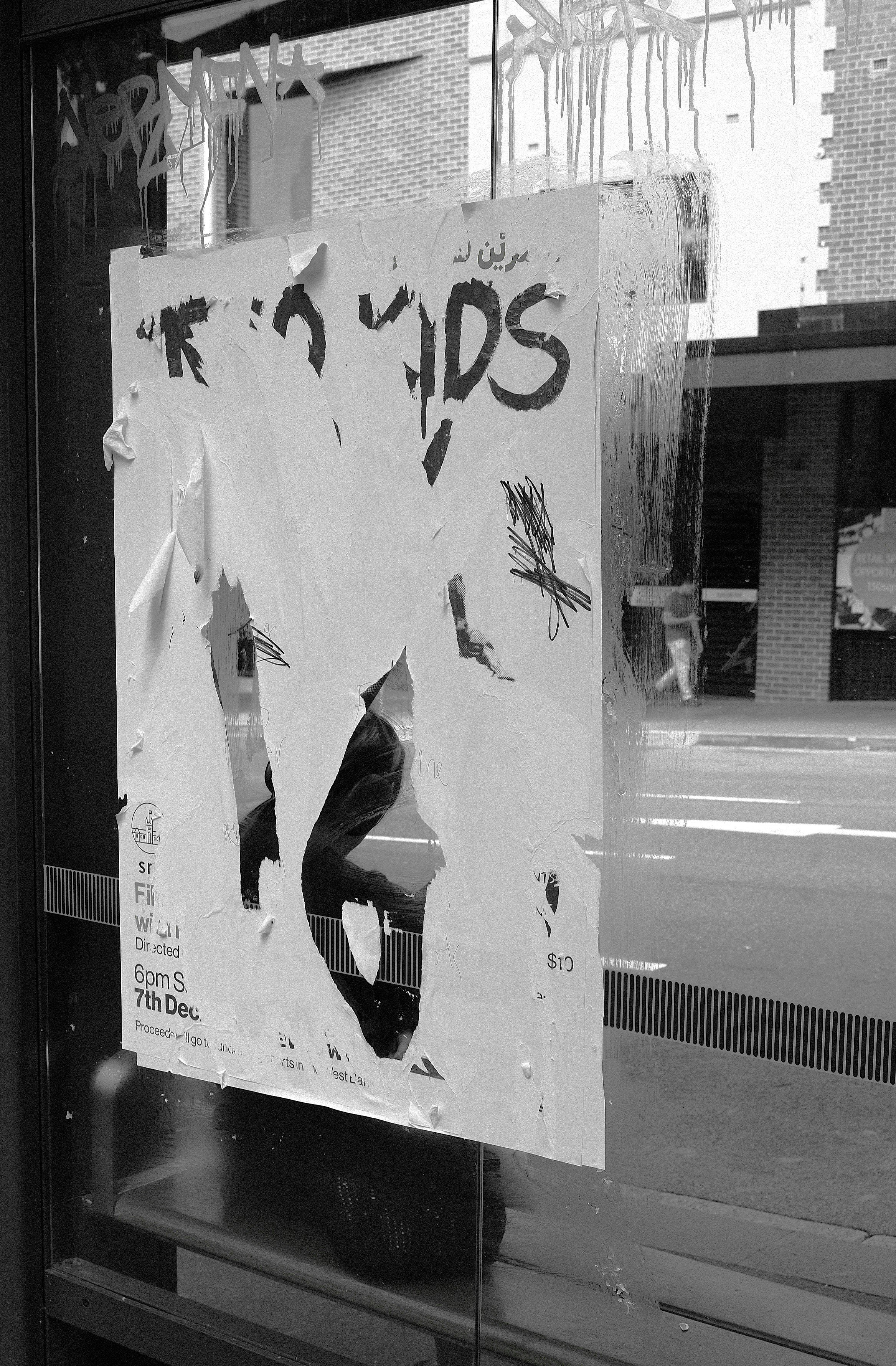 Shredded Poster on Glass: Street Reflections Split by Paper Fragments