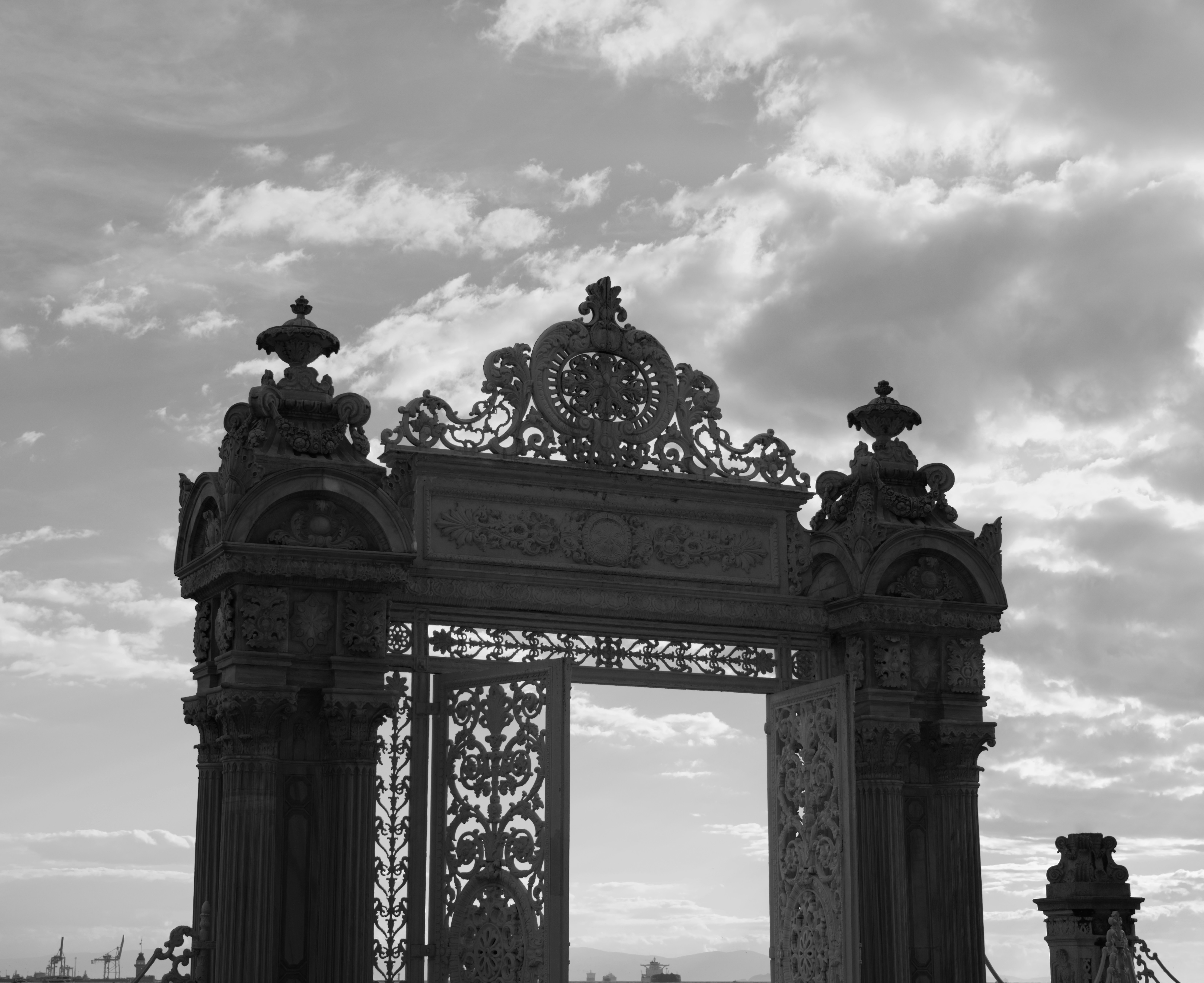 The Crowned Gate: Intricate Ironwork Framing a Clouded Sky