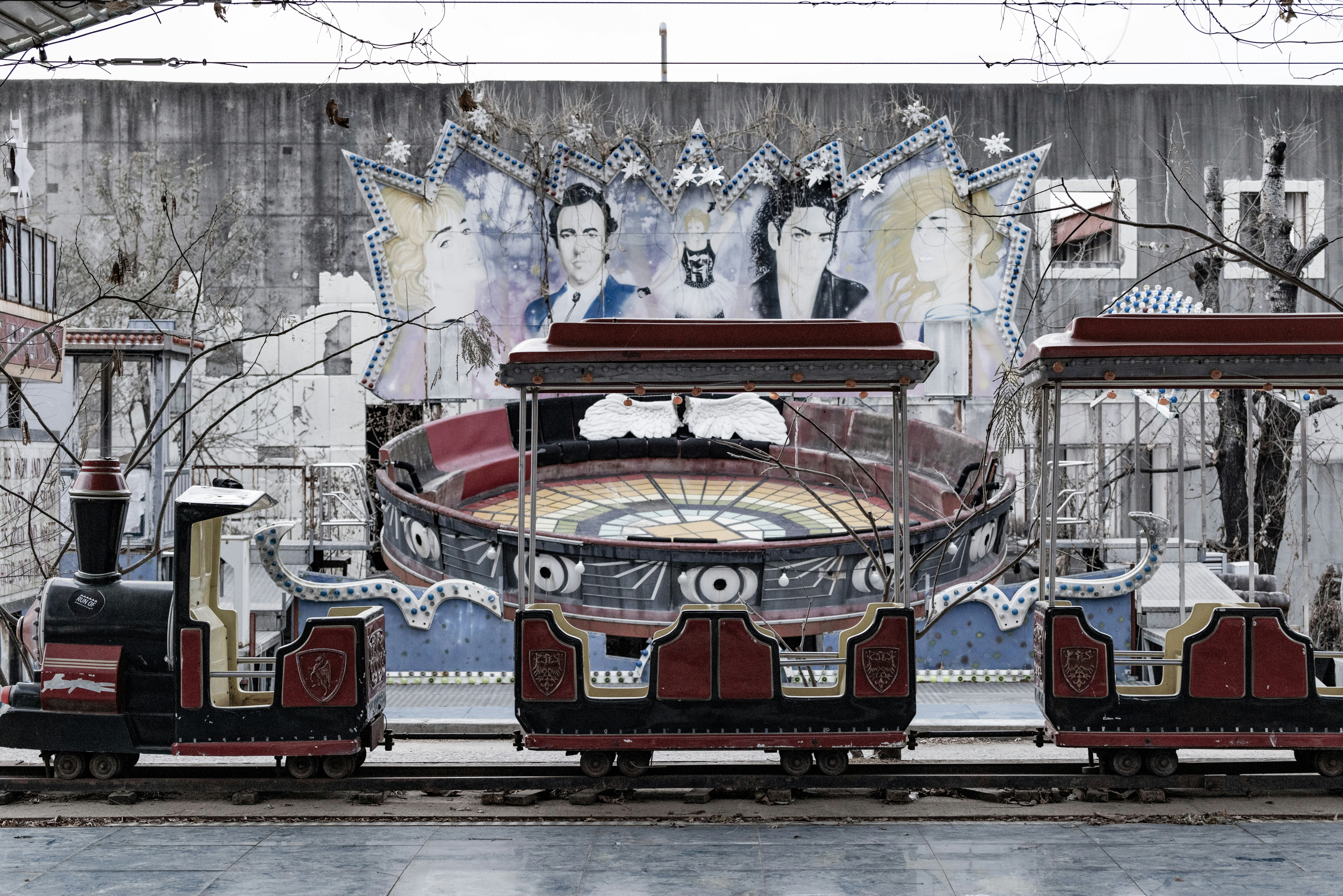 Graffiti Portraits Meet a Quiet Carousel Train in Winter's Urban Edge