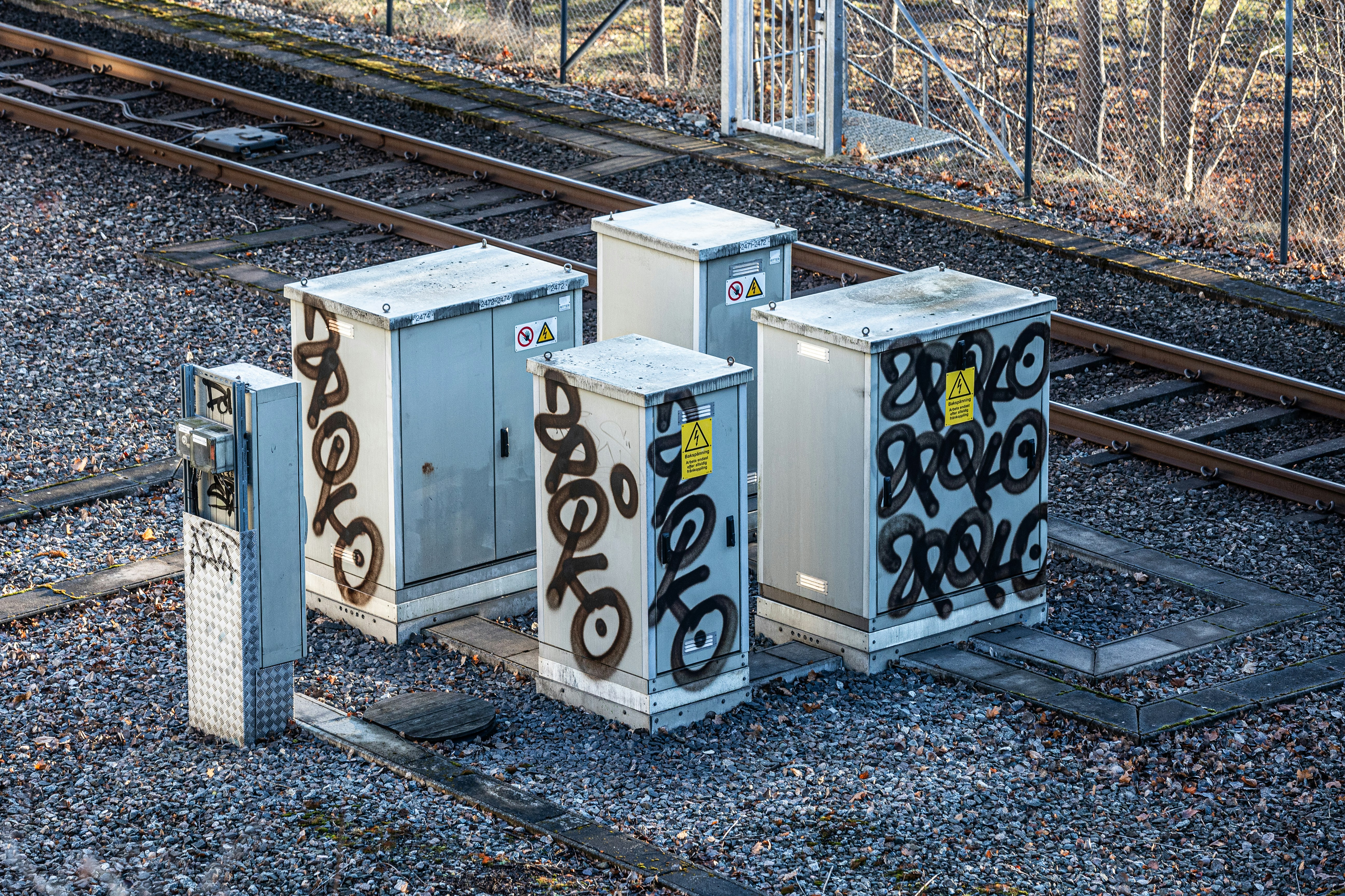 Graffiti-clad utility cabinets along gravel tracks