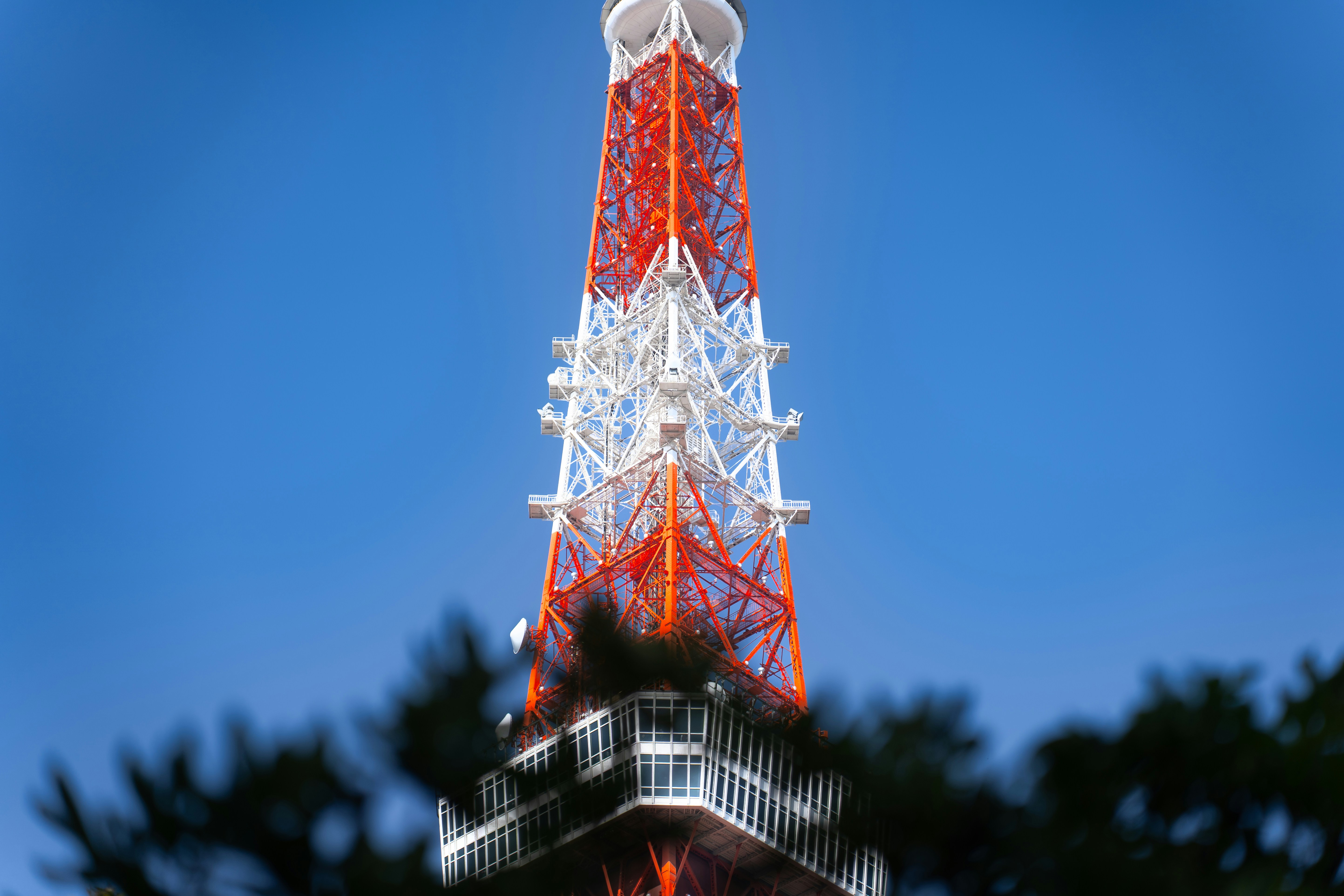 Tokyo Tower's red and white structure contrasts against a clear blue sky.