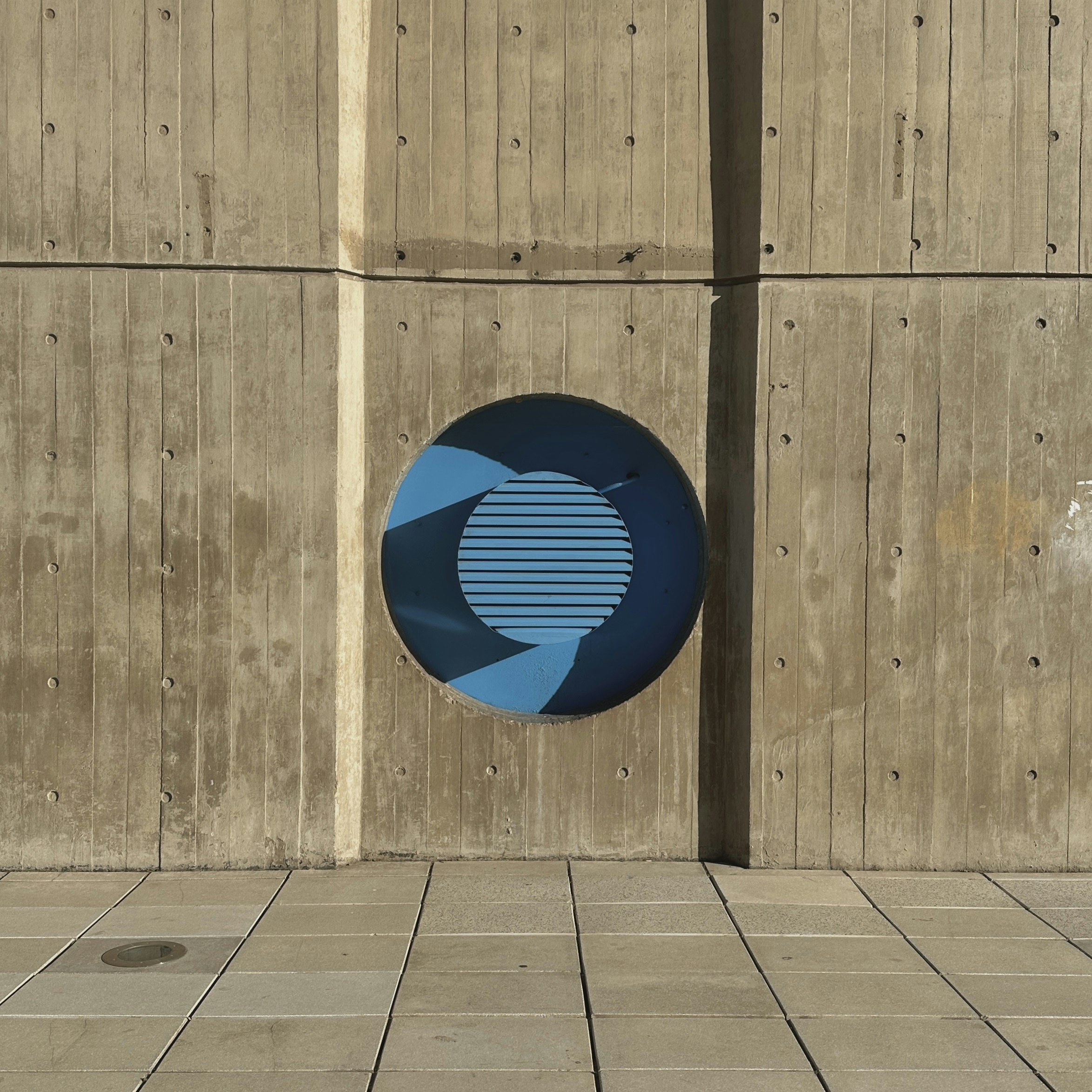 Cerulean Circle Embedded in a Facade of Weathered Concrete