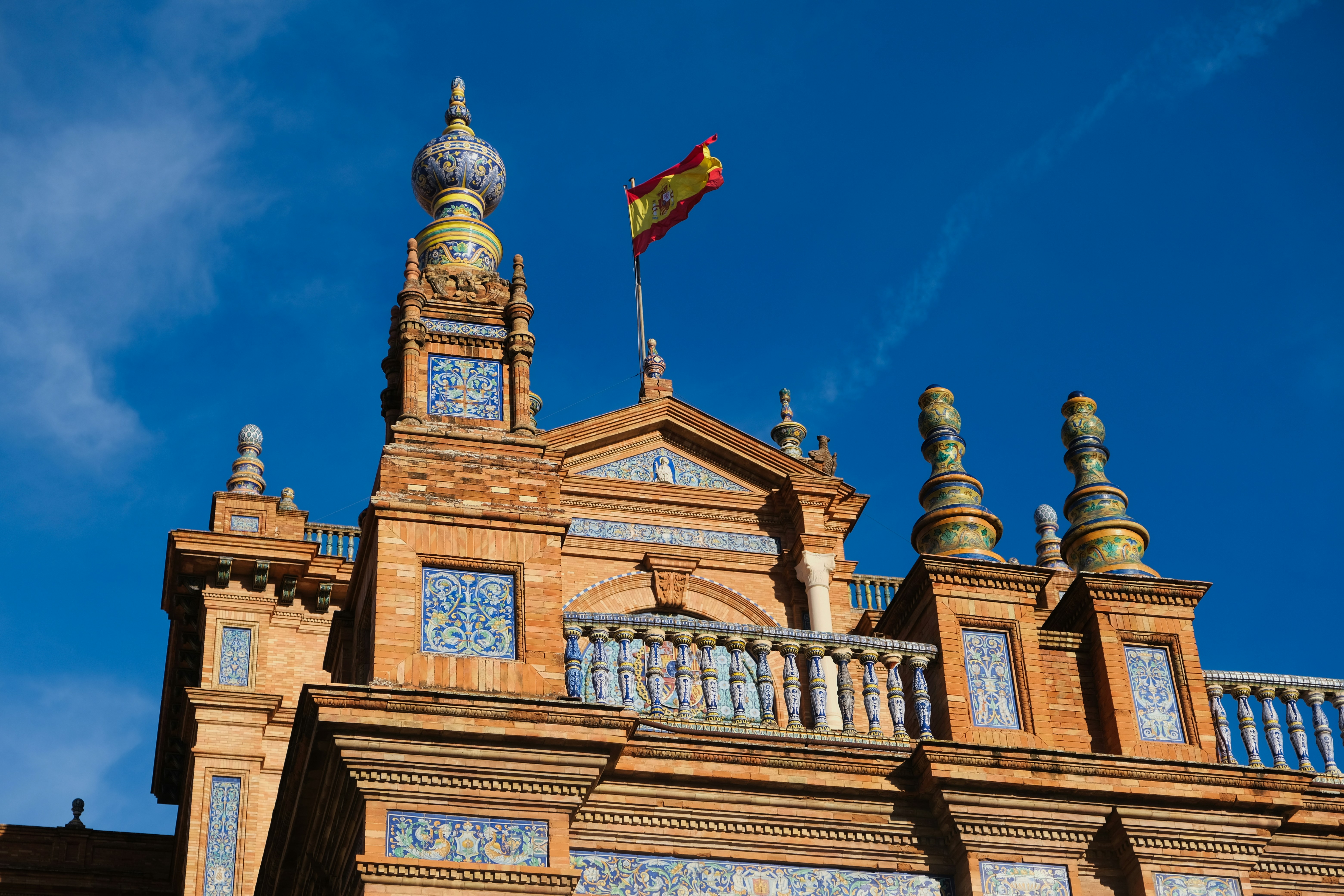 Ornate architectural details of a pavilion with a flag atop, set against a clear blue sky.