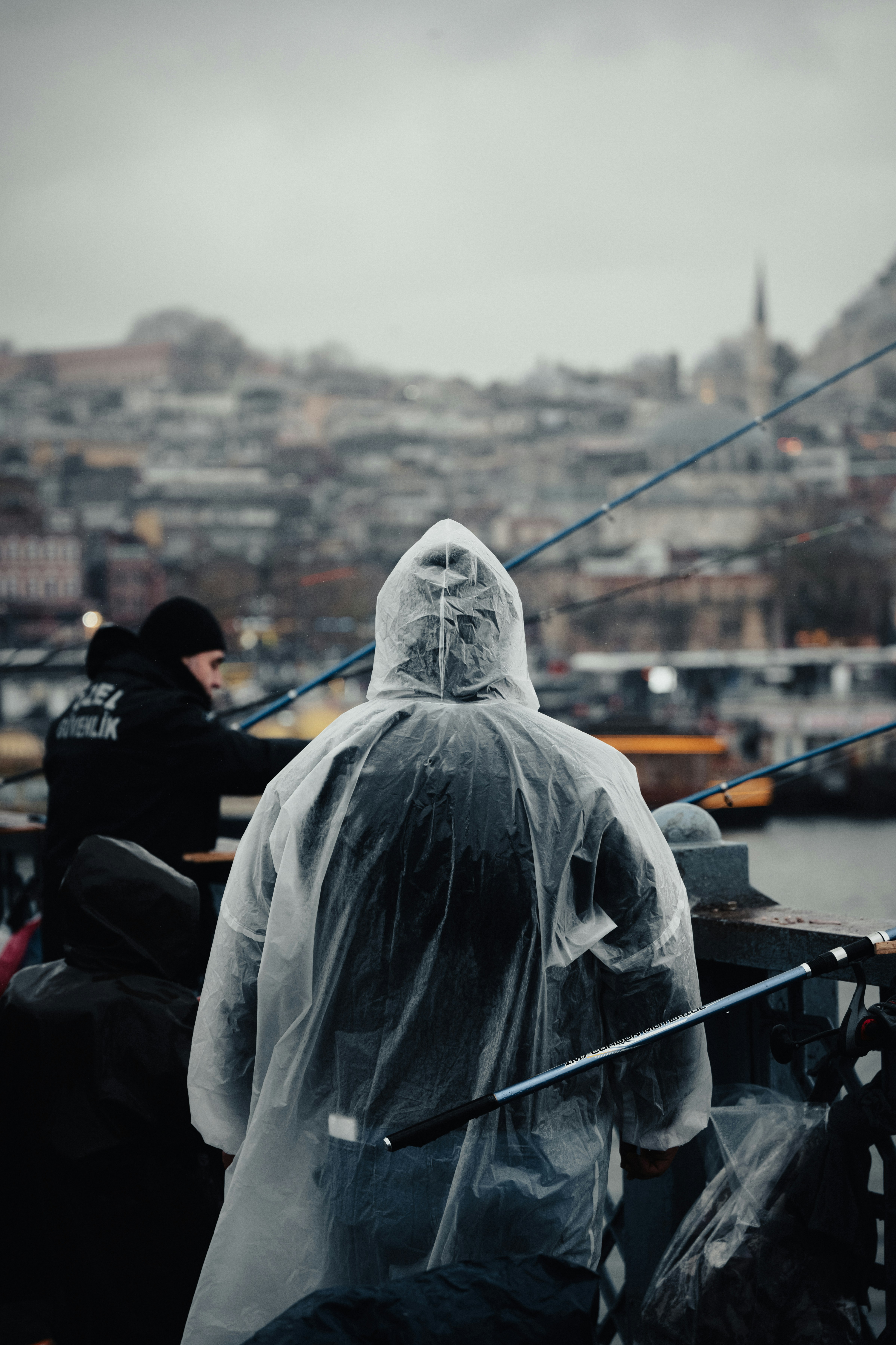 Hooded Figure on a Rain-Slick Harbor Deck