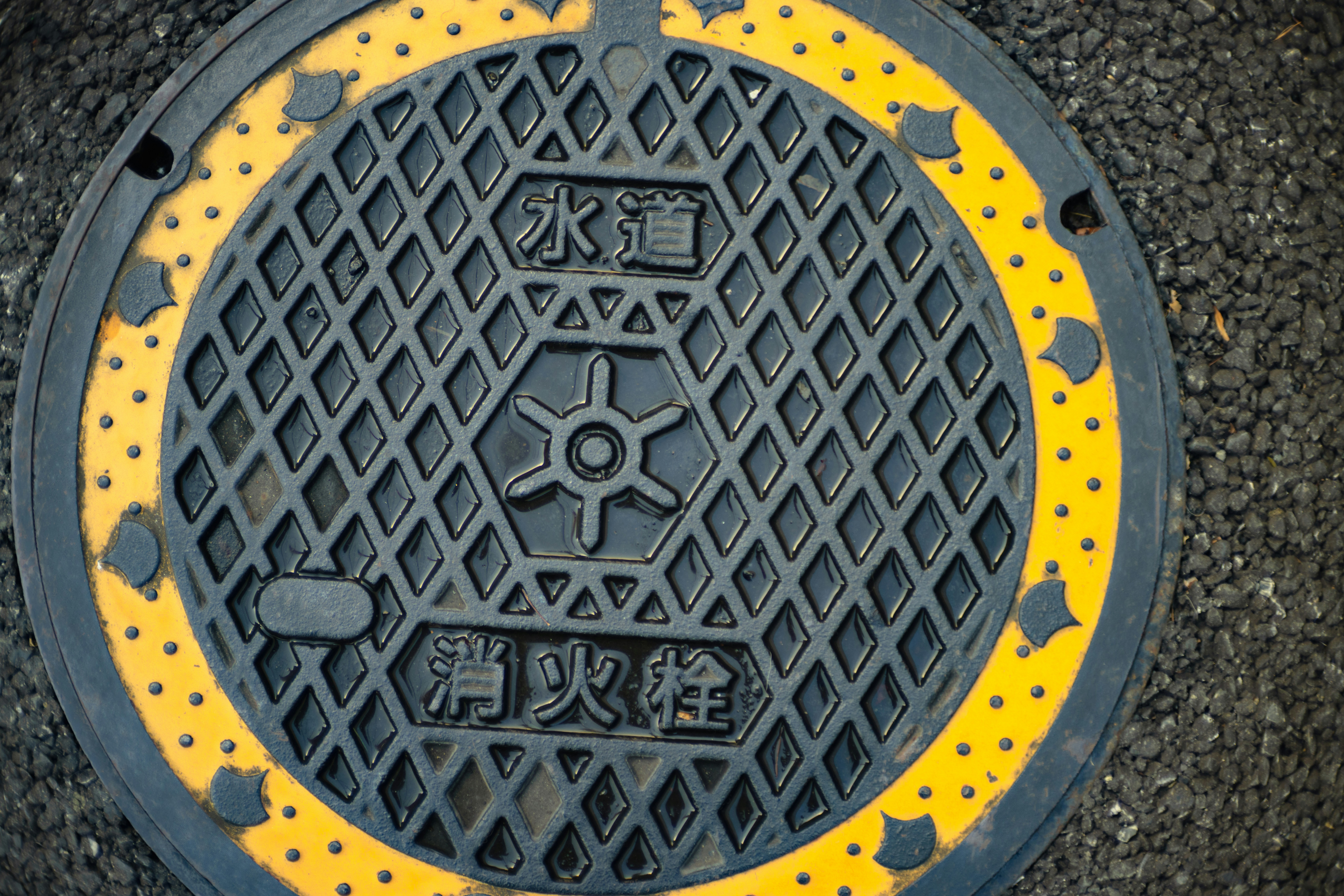 A yellow and black manhole cover on the ground photo – Free Hole Image ...