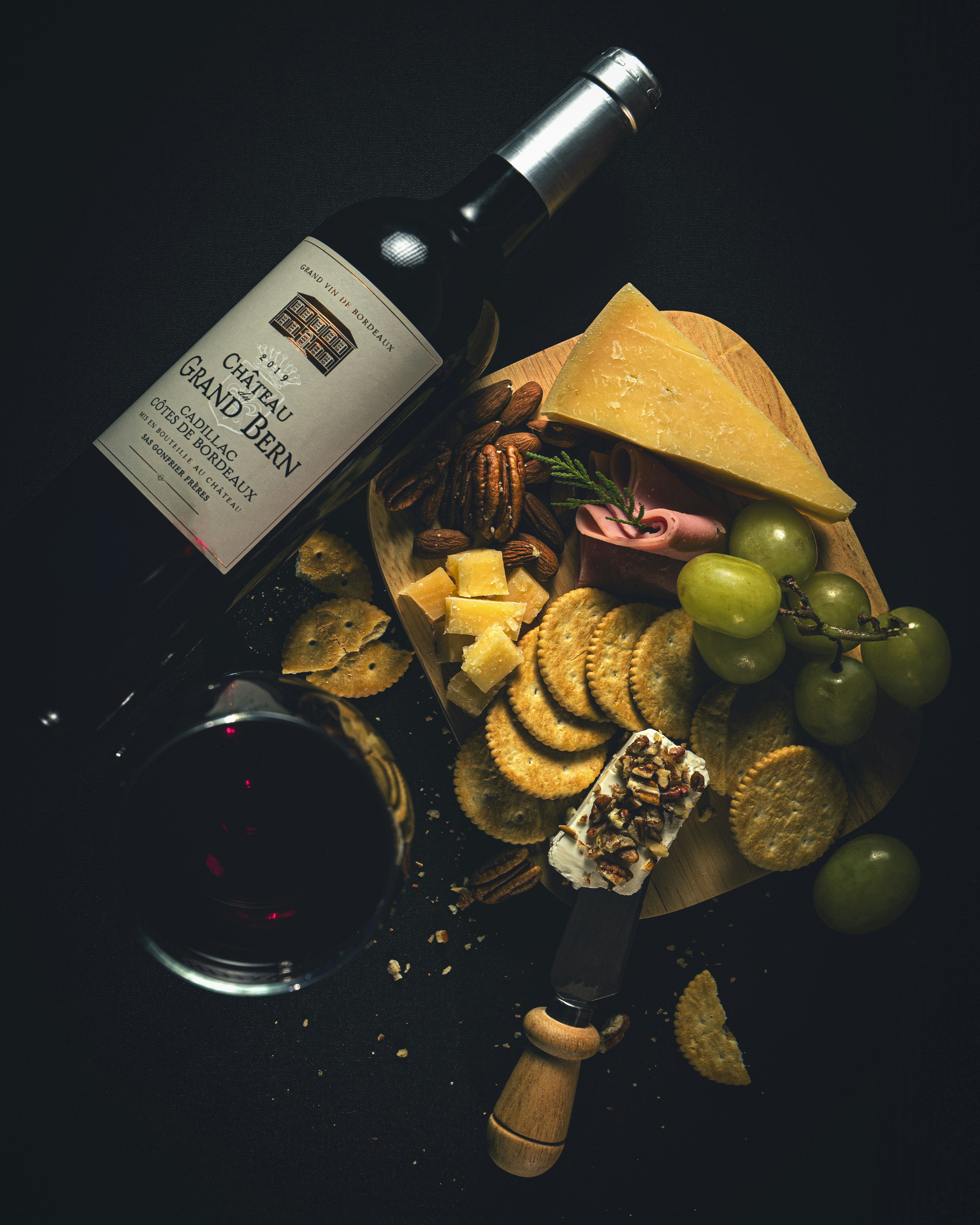 A bottle of wine sitting next to a bunch of grapes and crackers photo ...