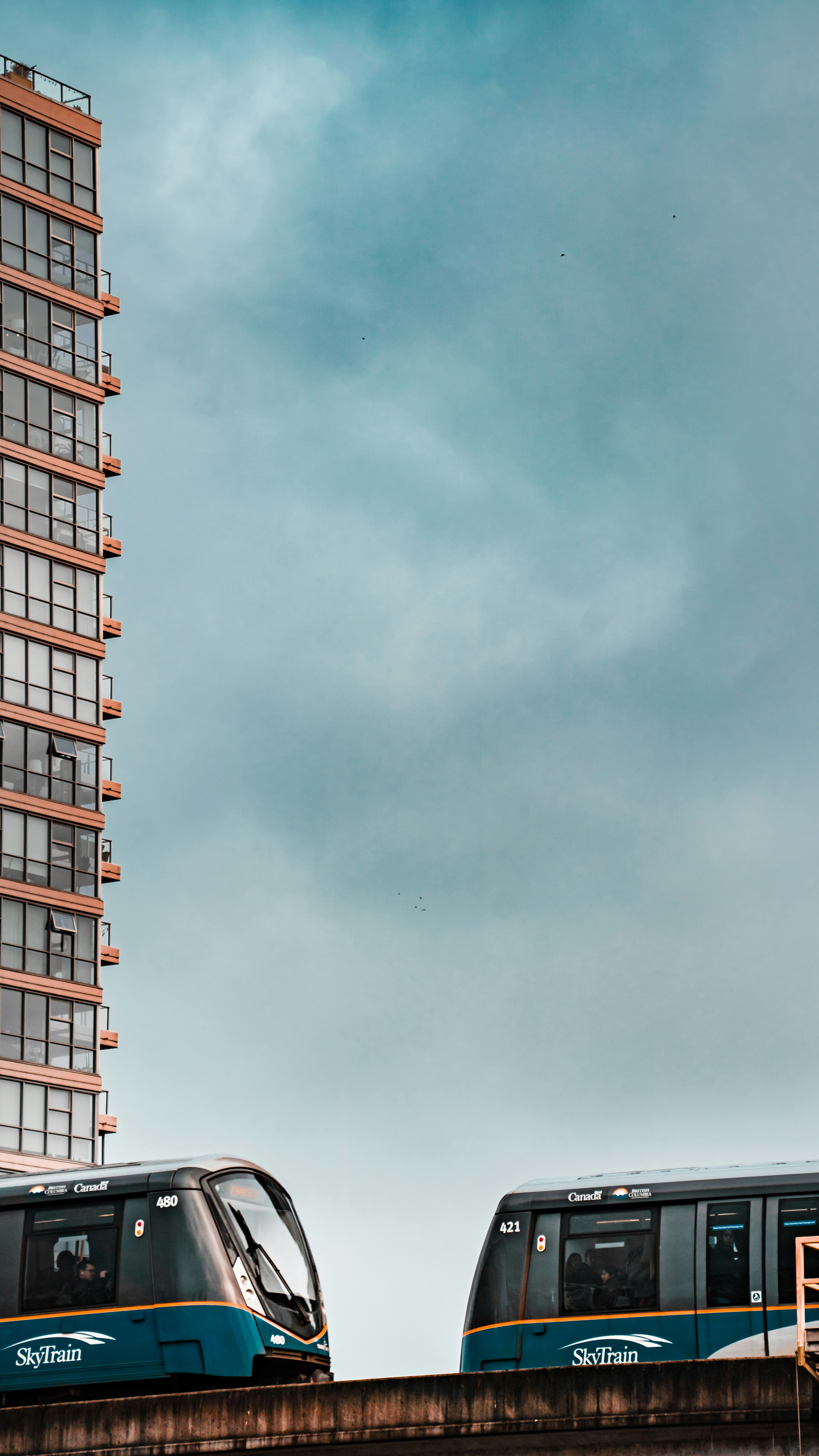 Two trains passing each other in front of a tall building photo – Free ...