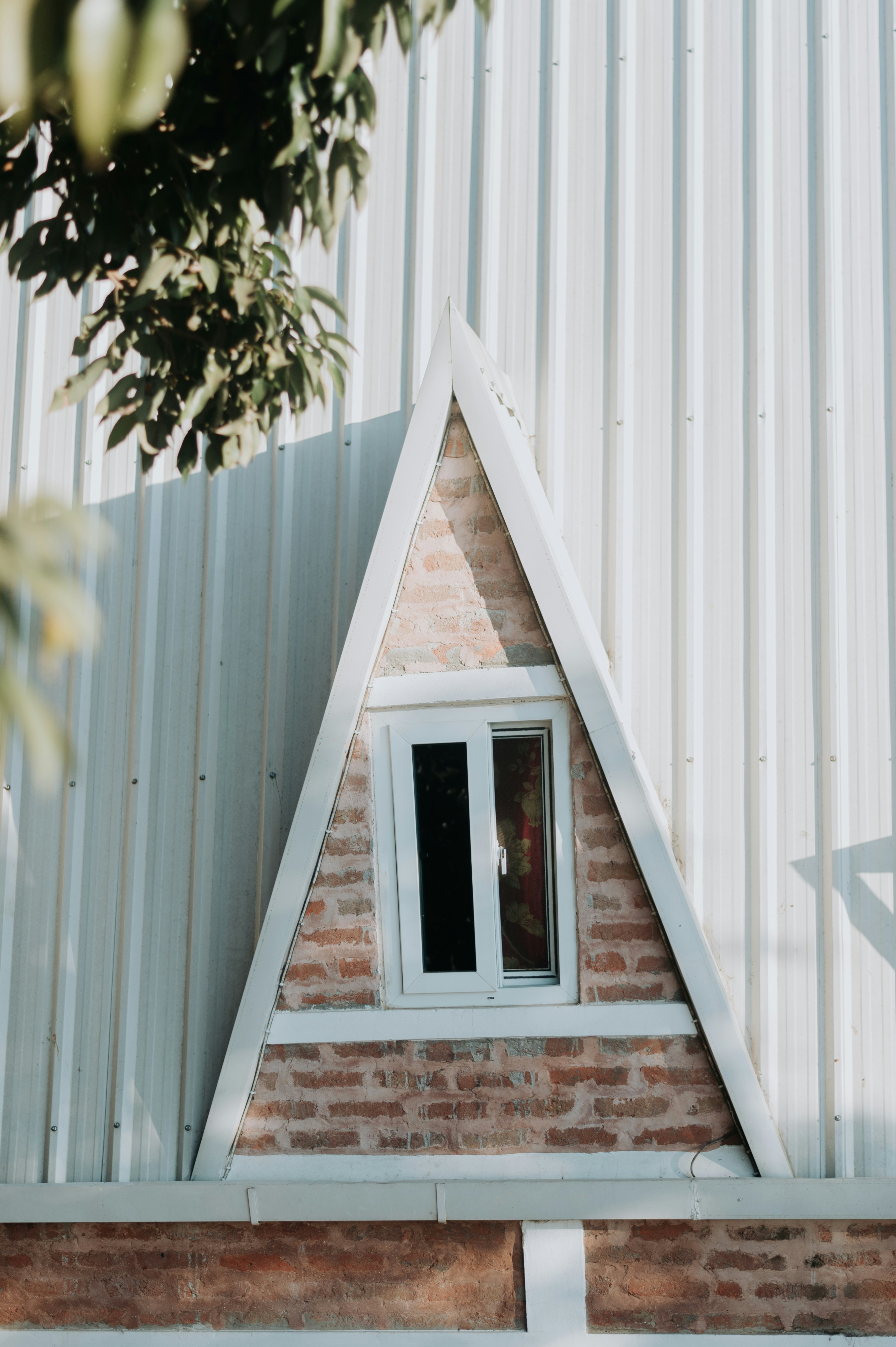 A building with a triangle shaped window on the side of it photo – Free ...