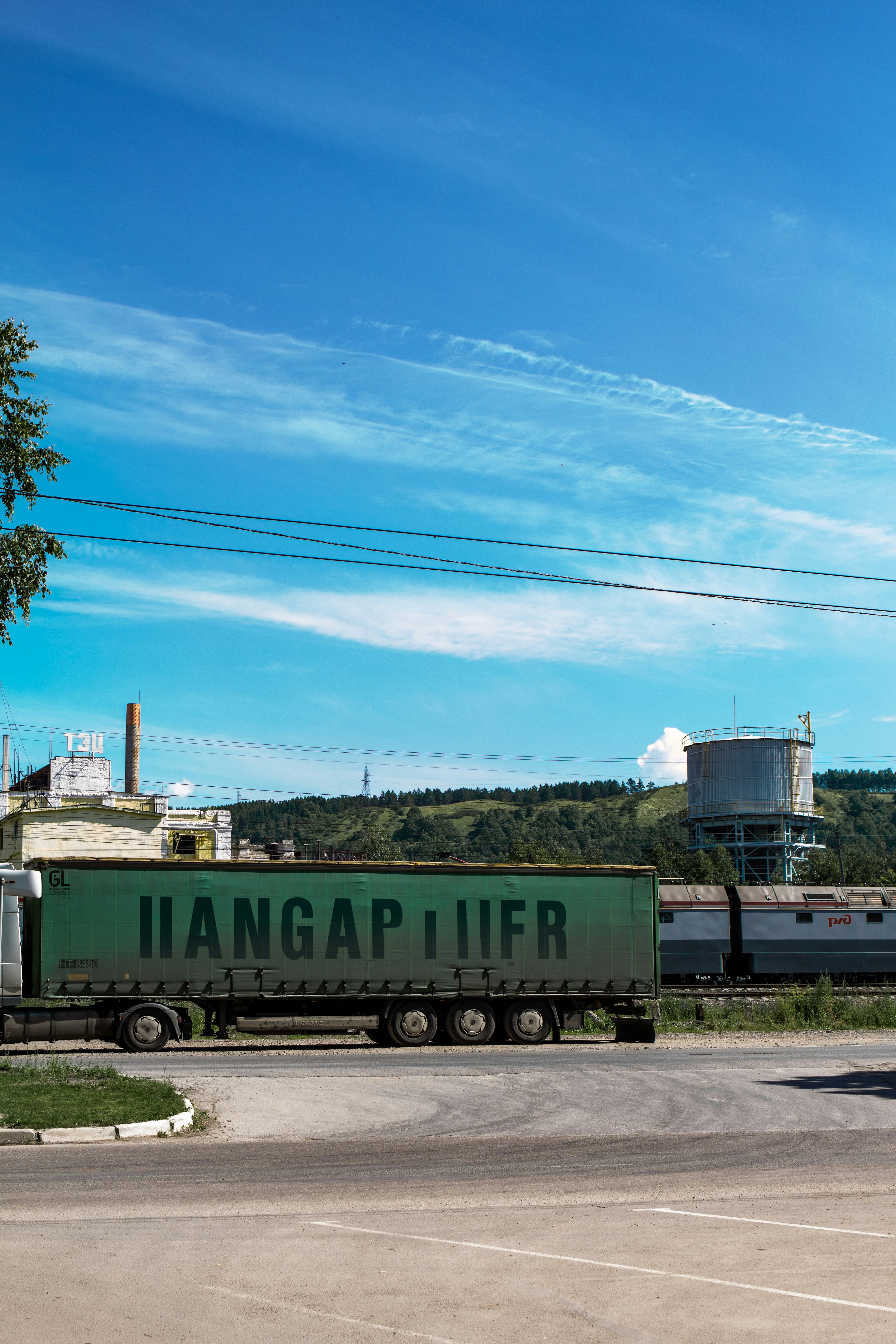 Green Freight Trailer Quietly Anchored in a Rail Yard Under a Wide Blue Sky
