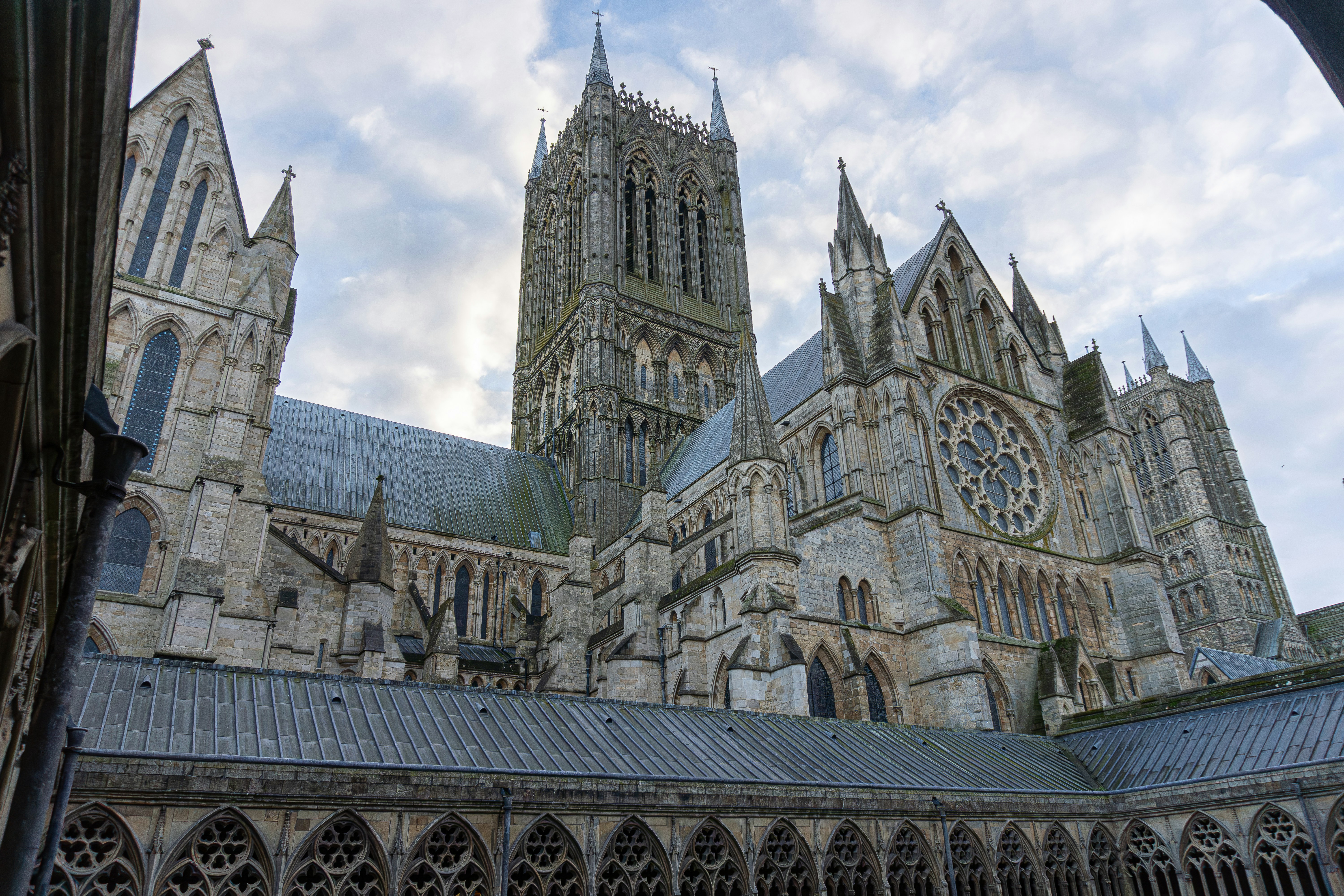 Lincoln Cathedral's intricate Gothic architecture rises against a backdrop of soft clouds.