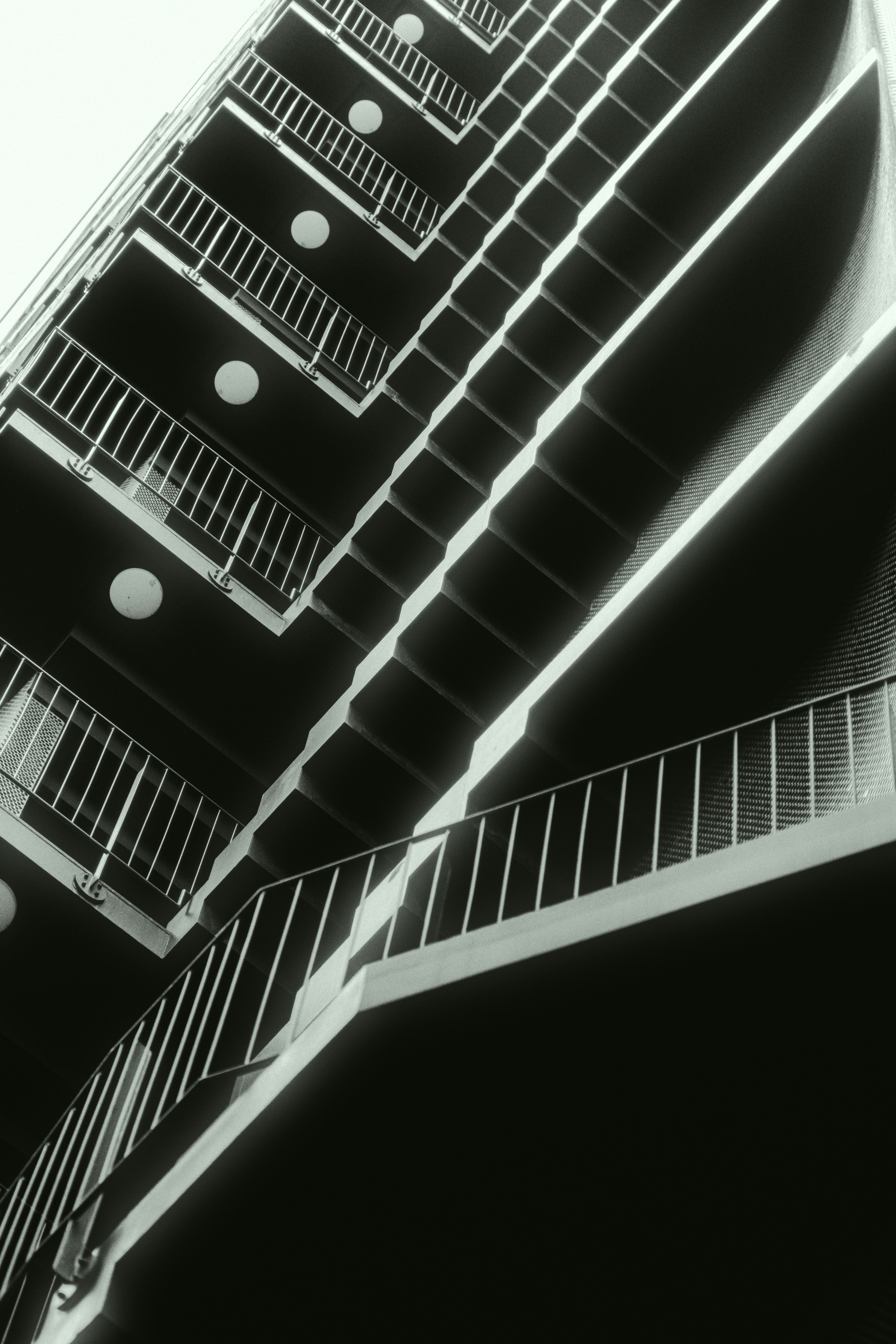 Monochrome Spiral Stairwell: Converging Rails and Shadowed Depth