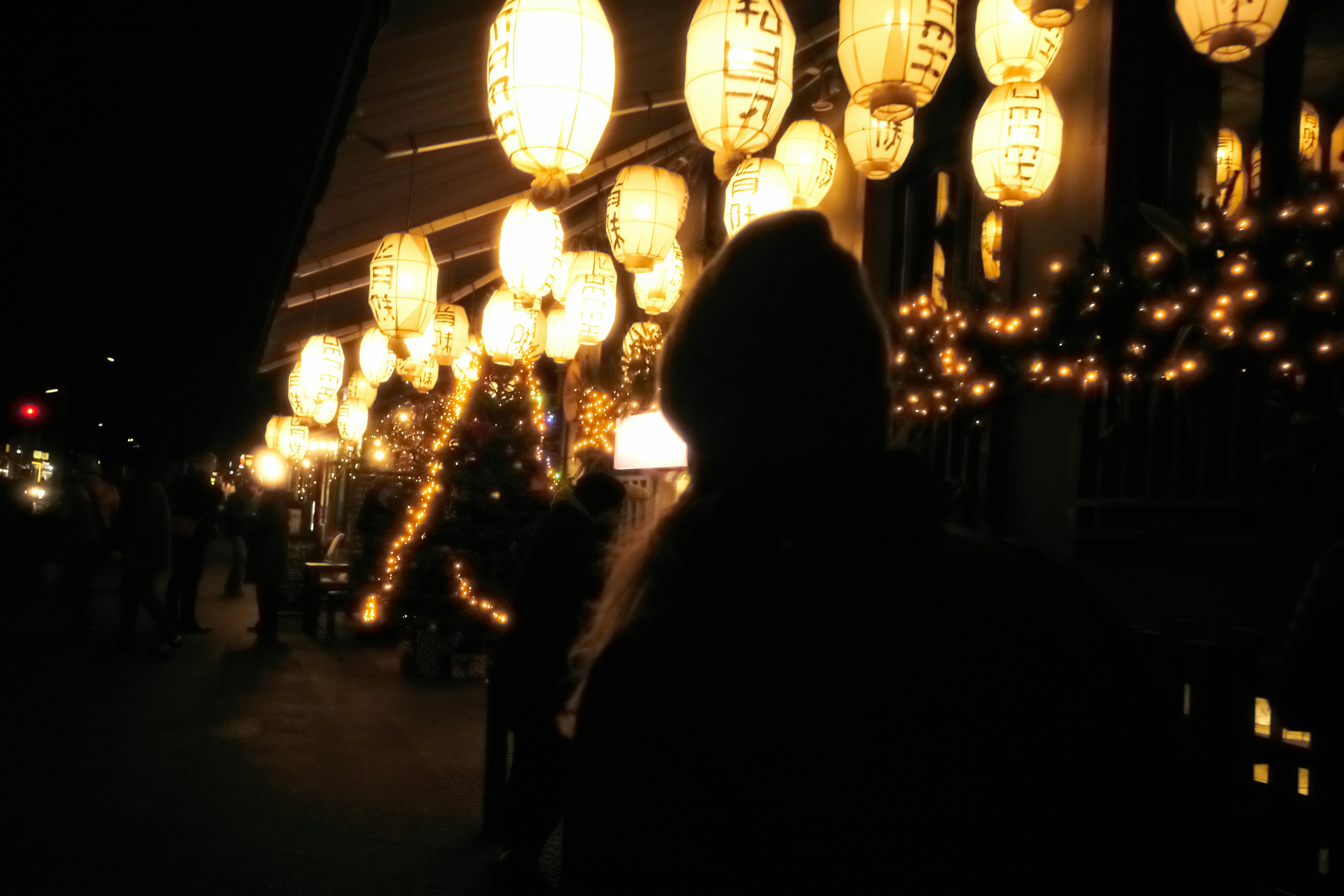 Shadowed silhouette under lantern glow in a festive night market