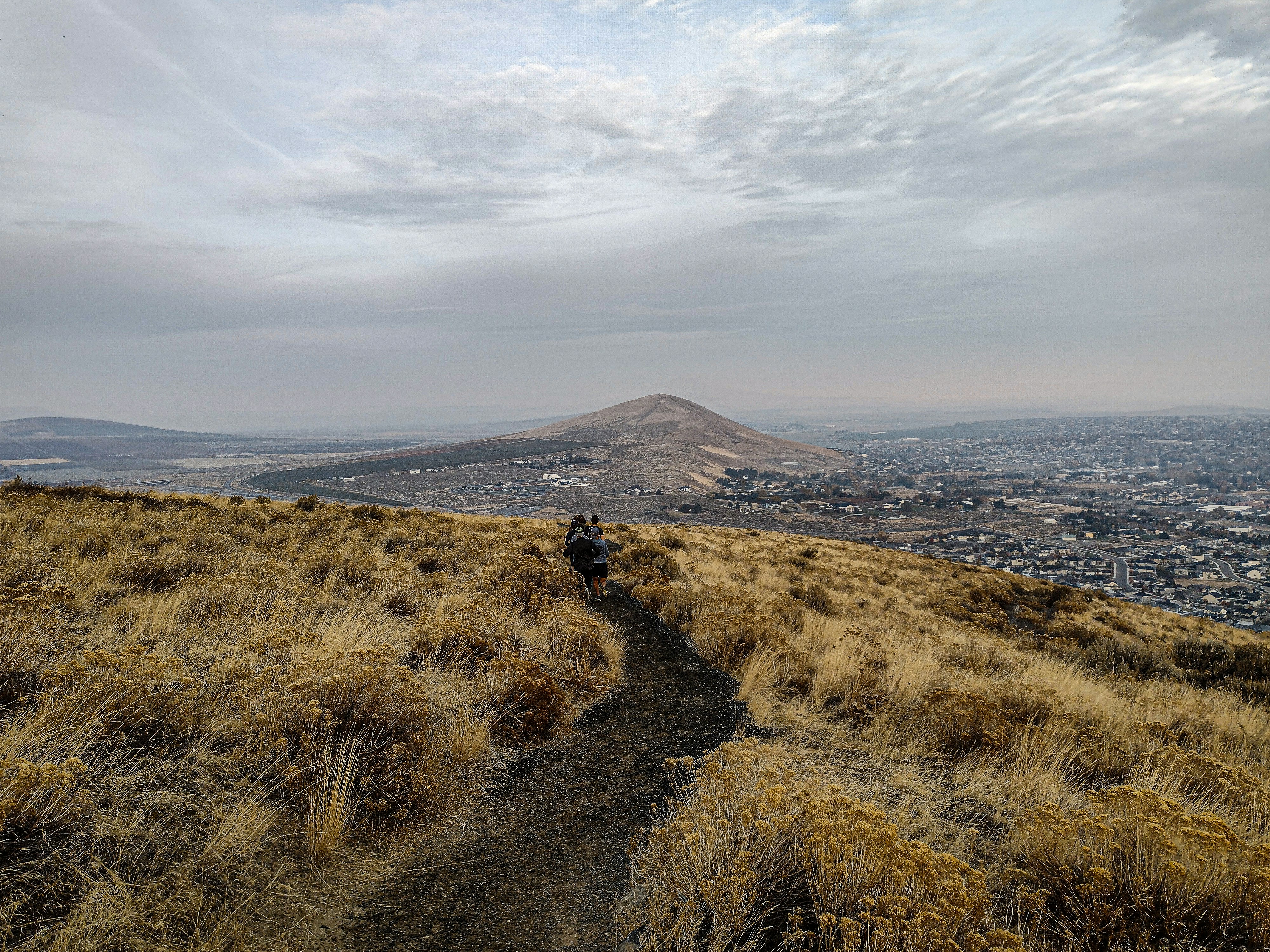 A trail going up a hill with a view of a city in the distance photo ...