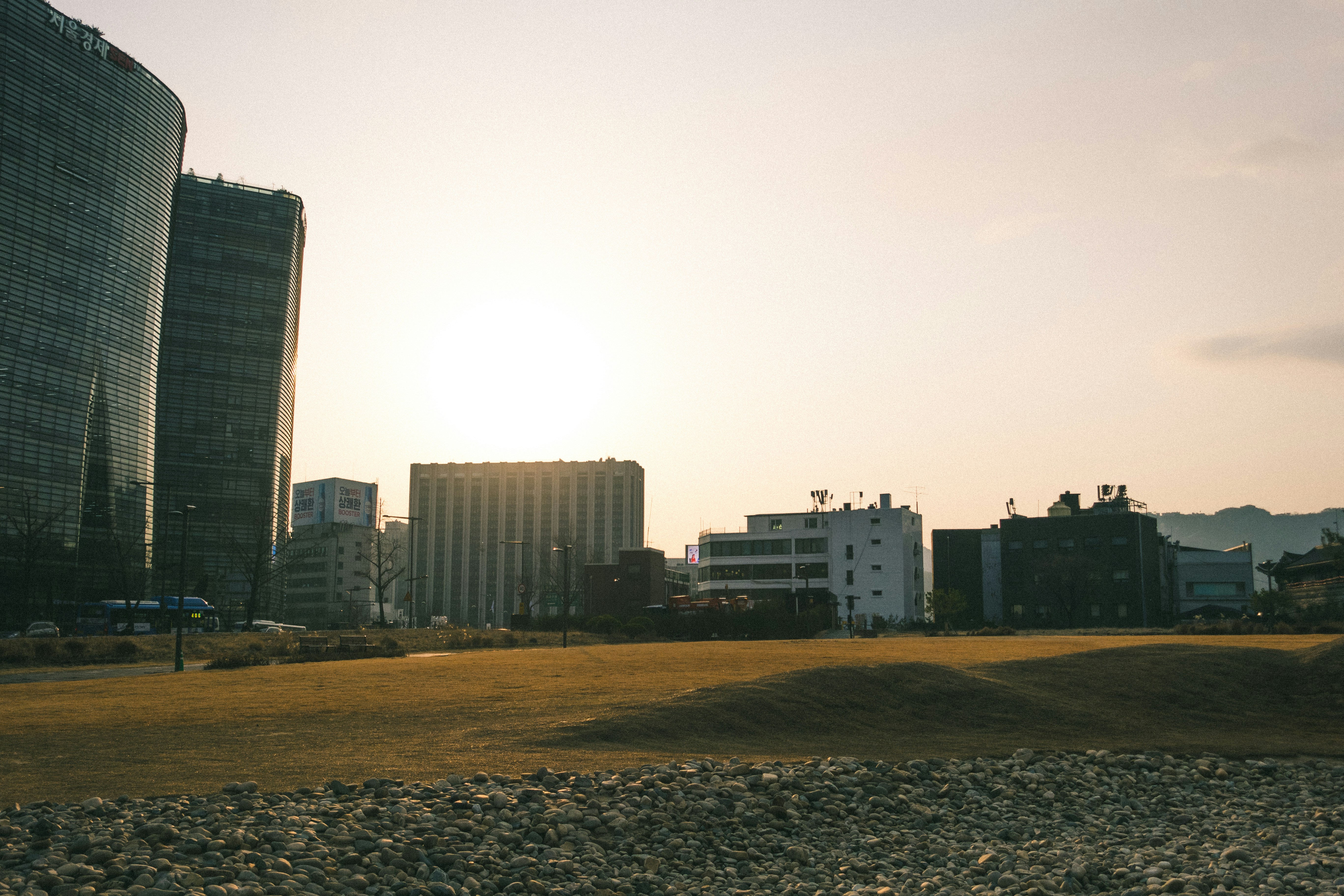 Sunset Over a Pebble Strip: Glass Giants Guarding a Quiet Riverside Park