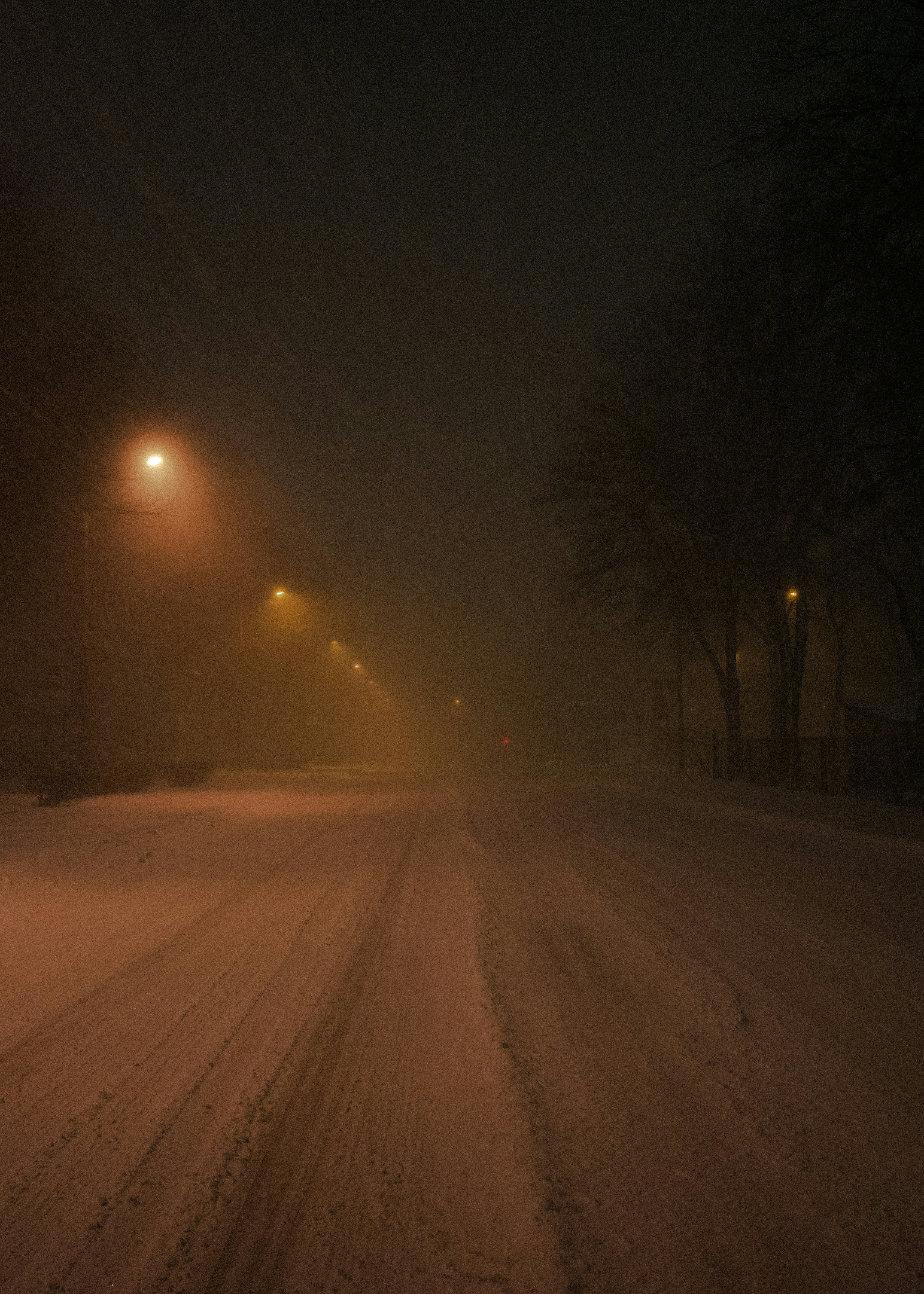 A snowy road at night with a street light in the distance photo – Free ...