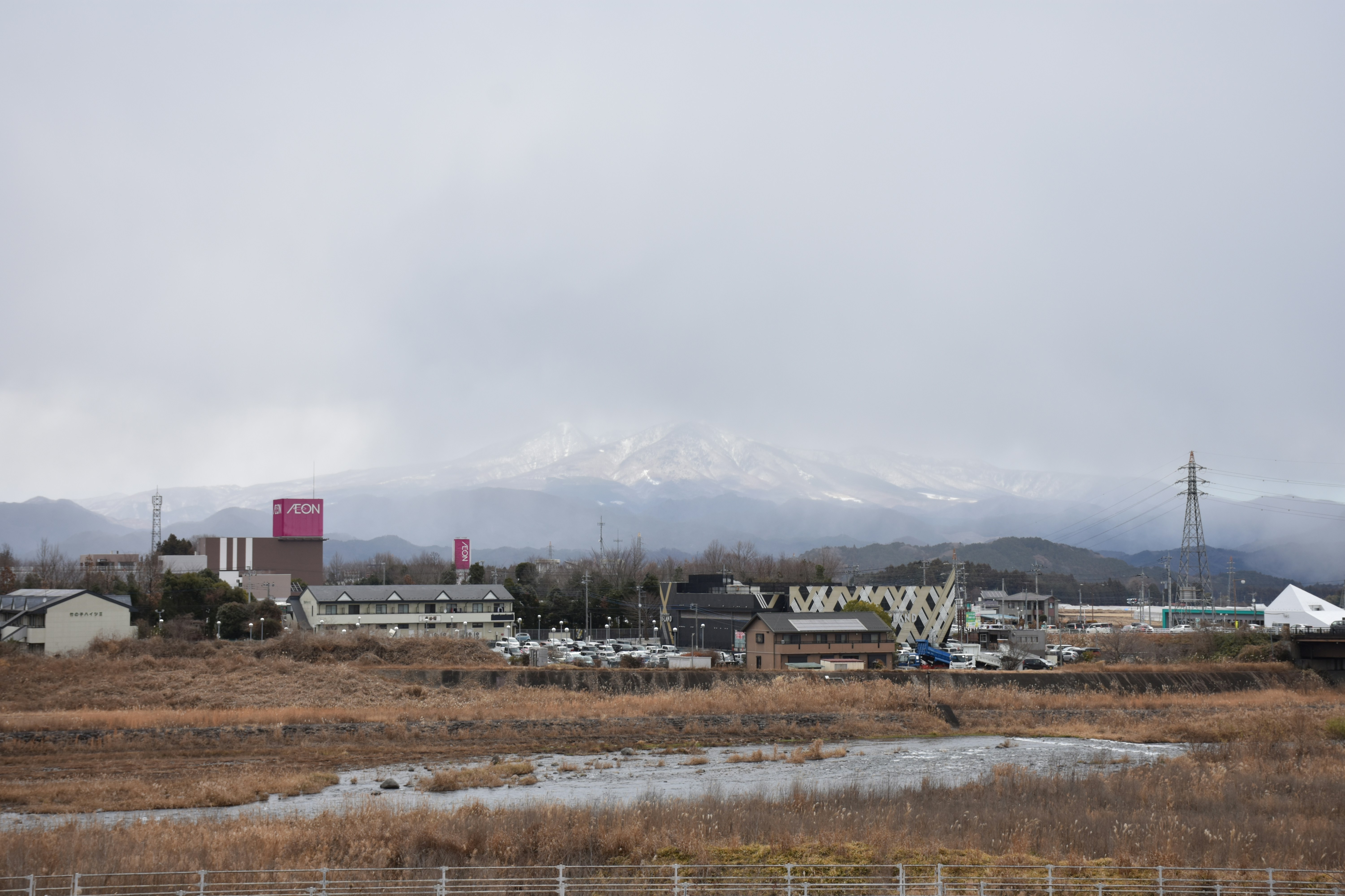 Pink Sign Over a Prairie Town Toward Snow-Capped Peaks