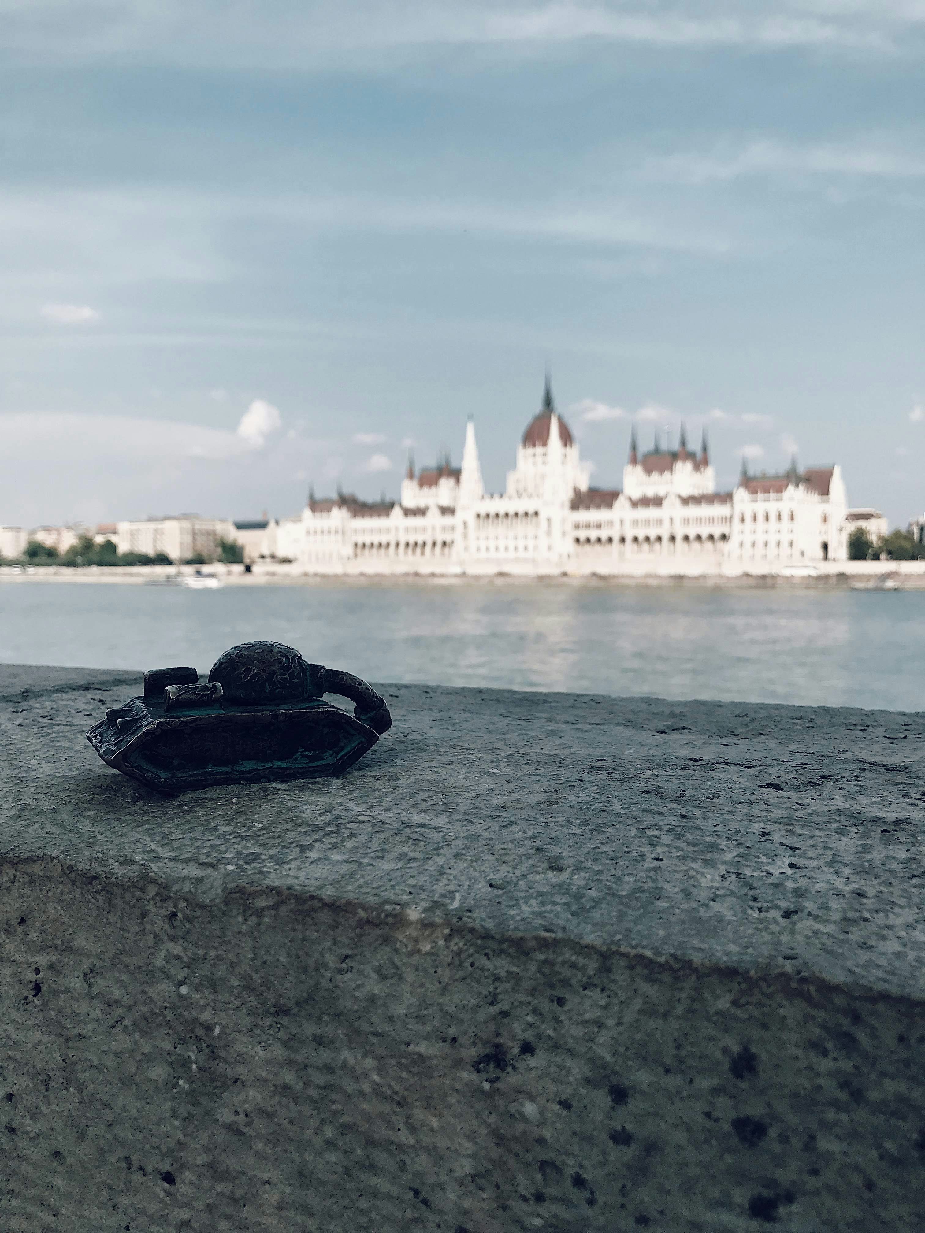 Grey pebble with distant fortress across a calm harbor