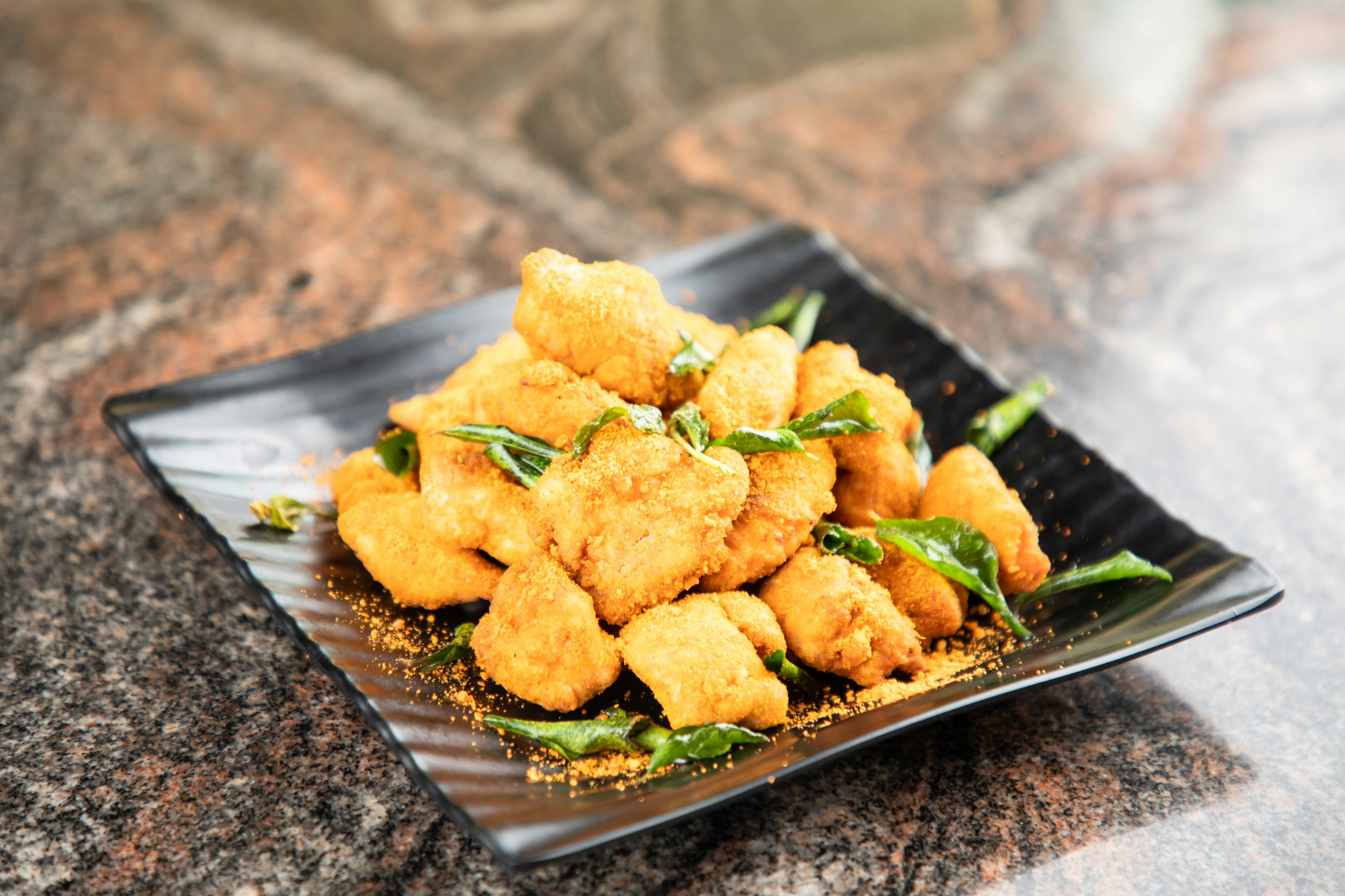 A black plate topped with fried food on top of a counter photo – Free ...