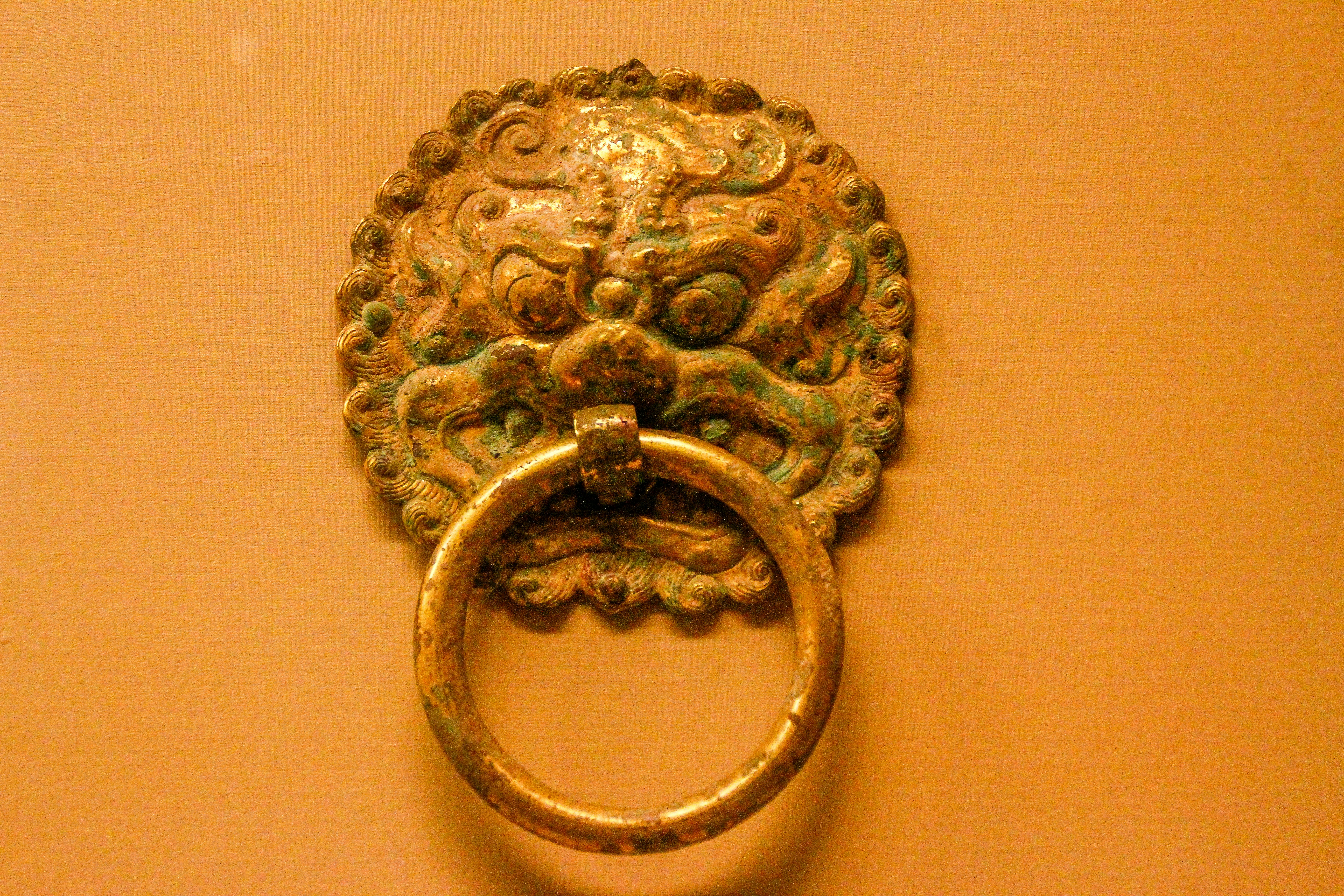 Intricately designed bronze door knocker featuring a mythical creature, showcasing craftsmanship from a bygone era.