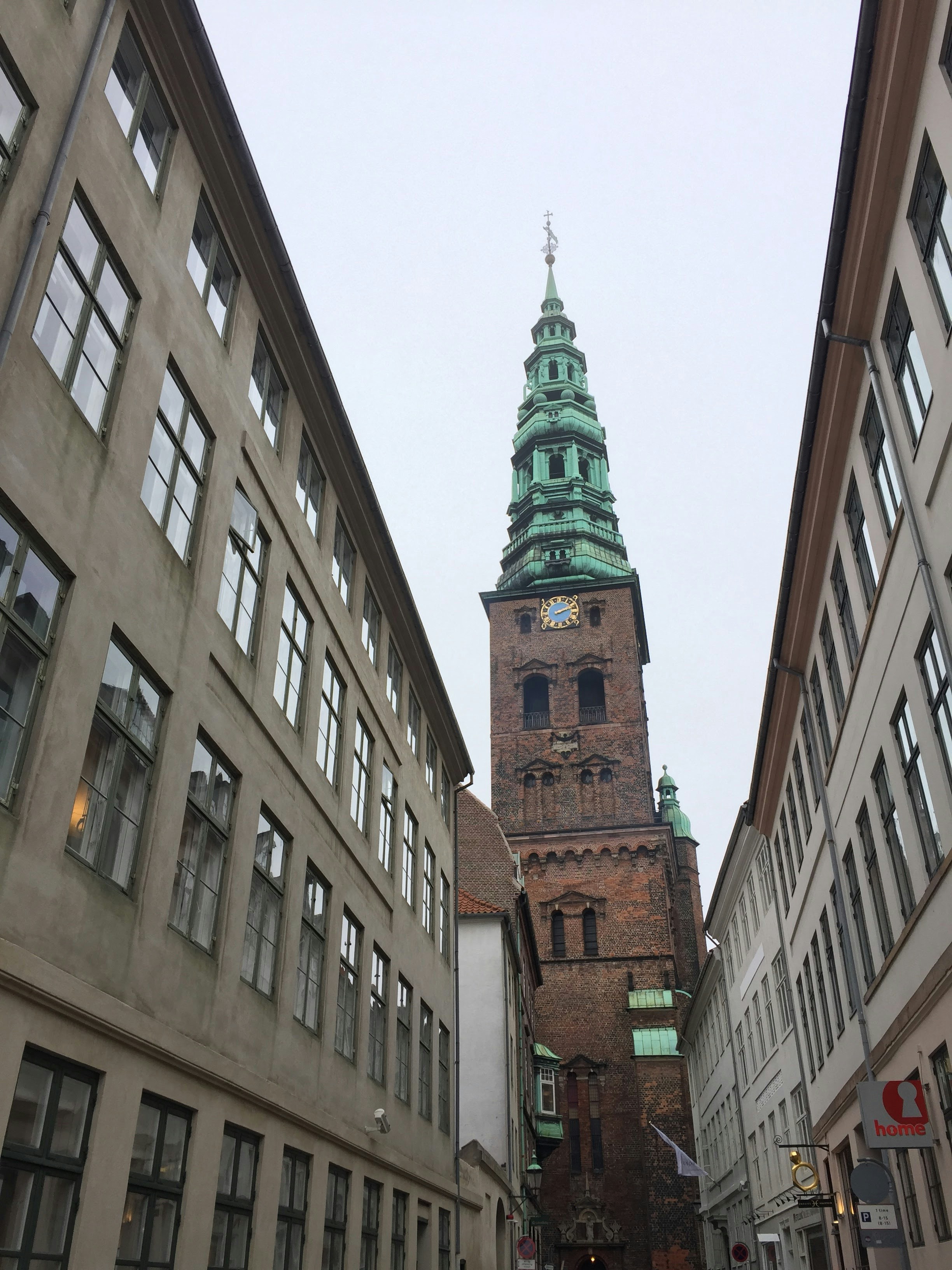 Verdigris Spire Between Narrow Facades: A Street Portrait of Architectural Rhythm