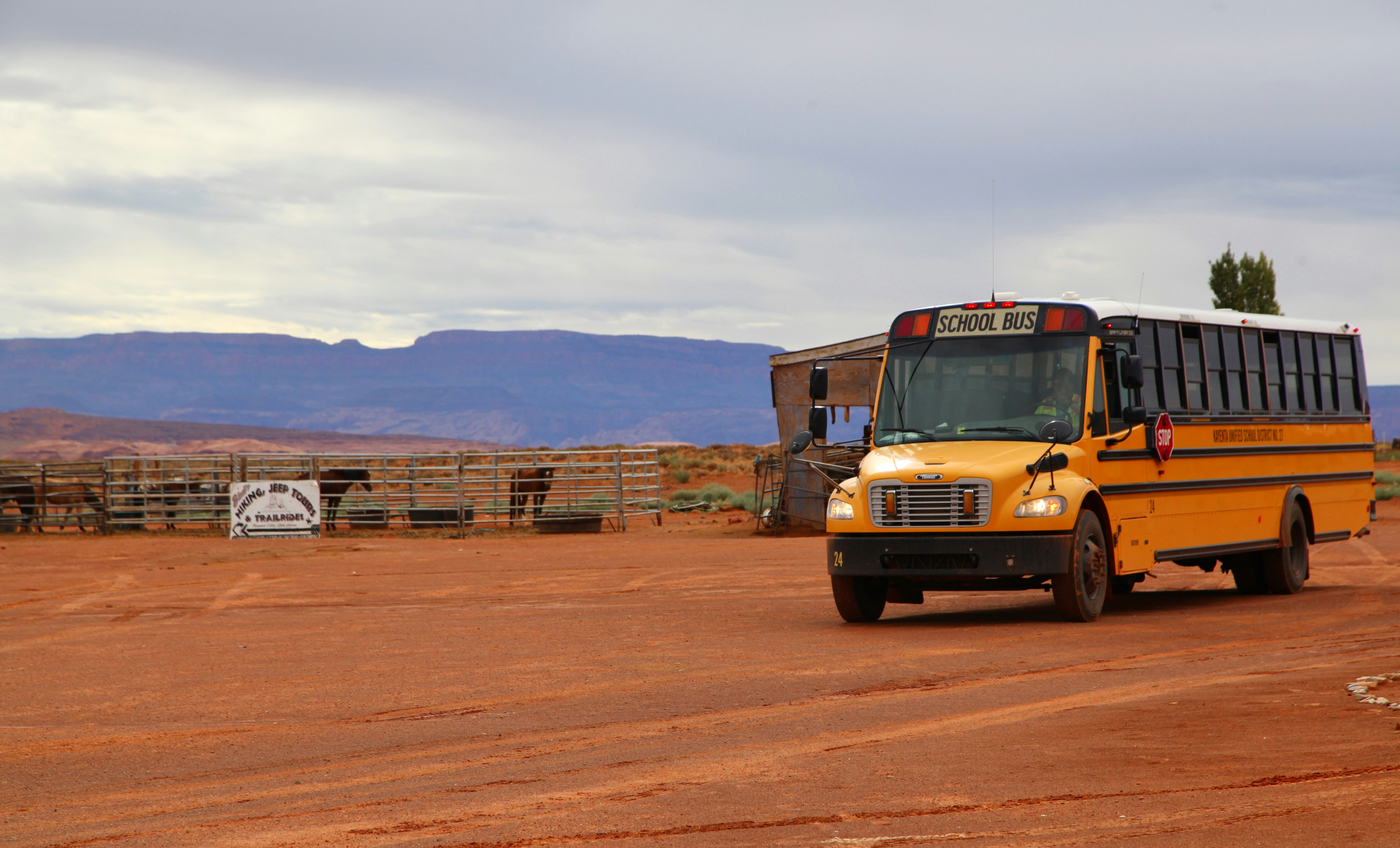 Yellow School Bus on a Rust-Red Desert Plain Beneath Expansive Desert Sky