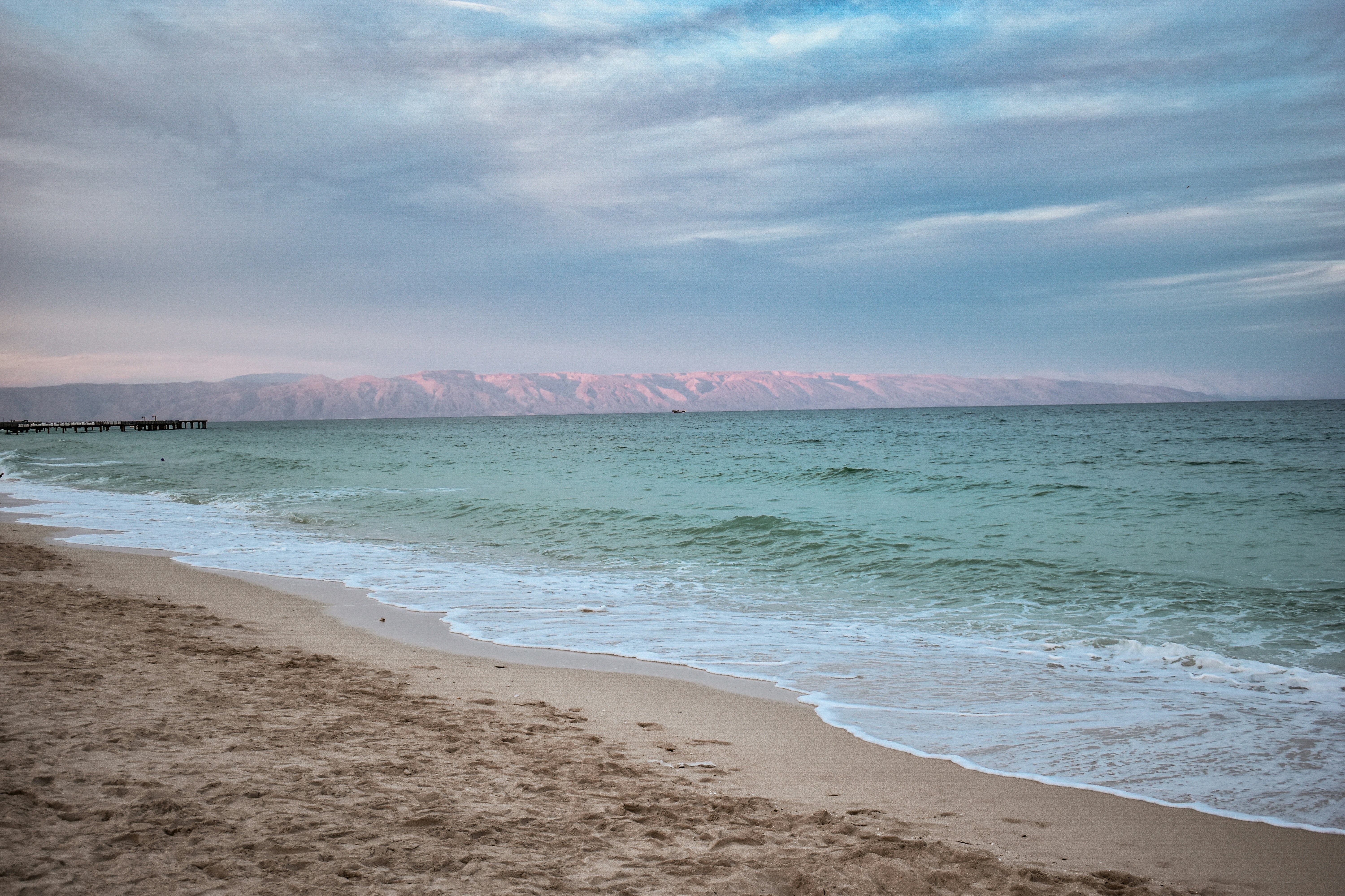 A sandy beach with waves coming in to shore photo – Free Kish island ...