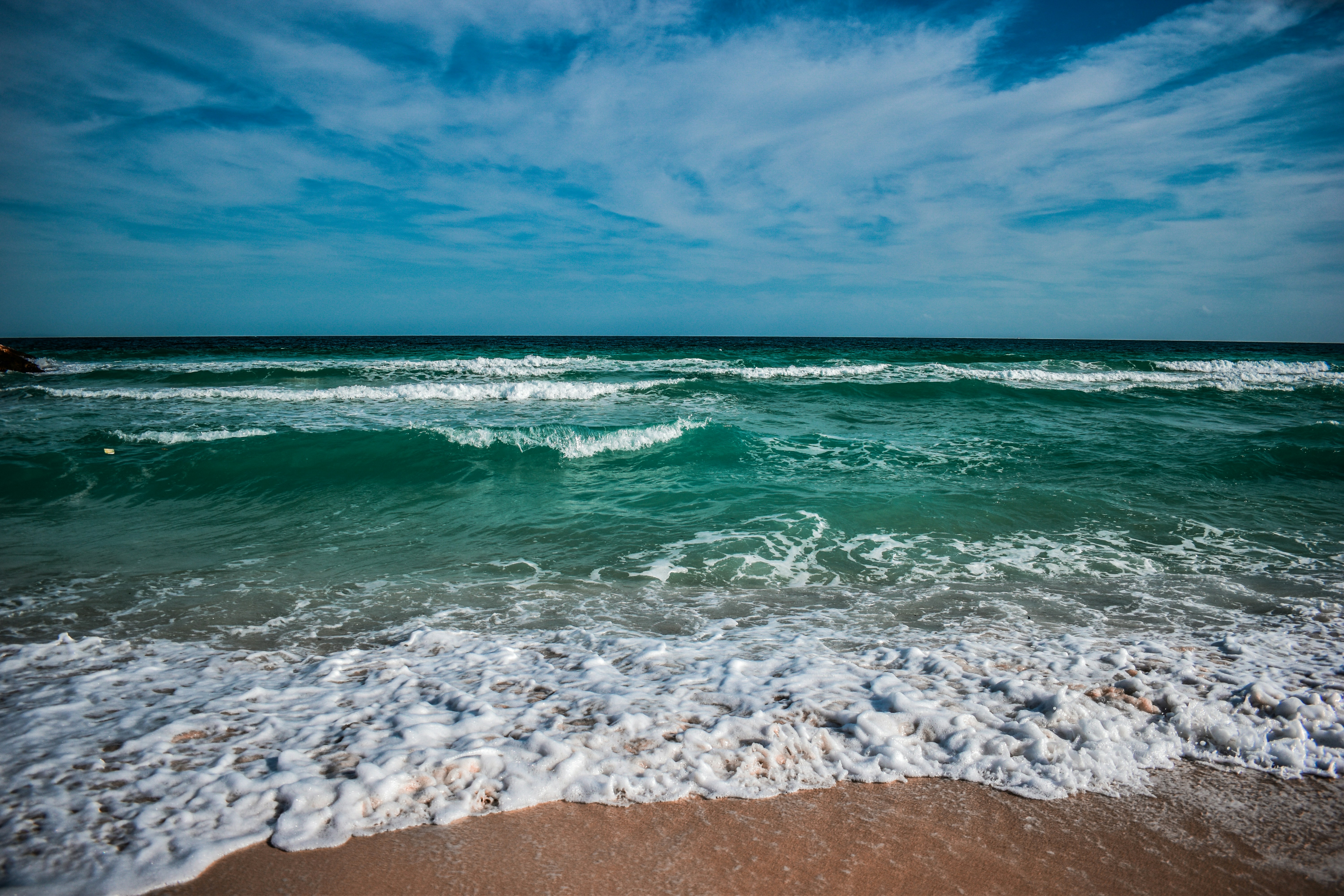 A sandy beach with waves coming in to shore photo – Free Kish island ...
