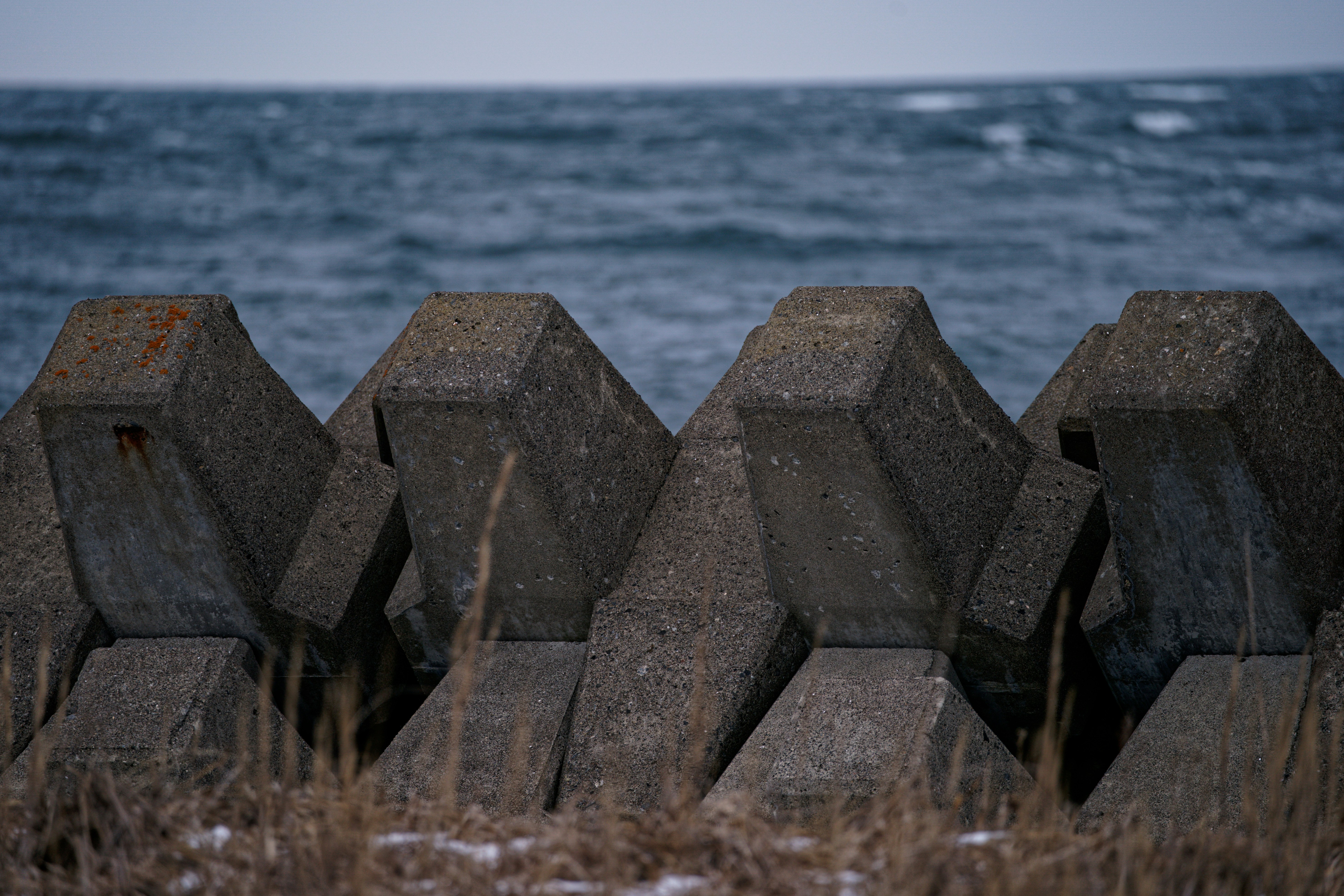 A row of concrete blocks sitting next to a body of water photo – Free ...