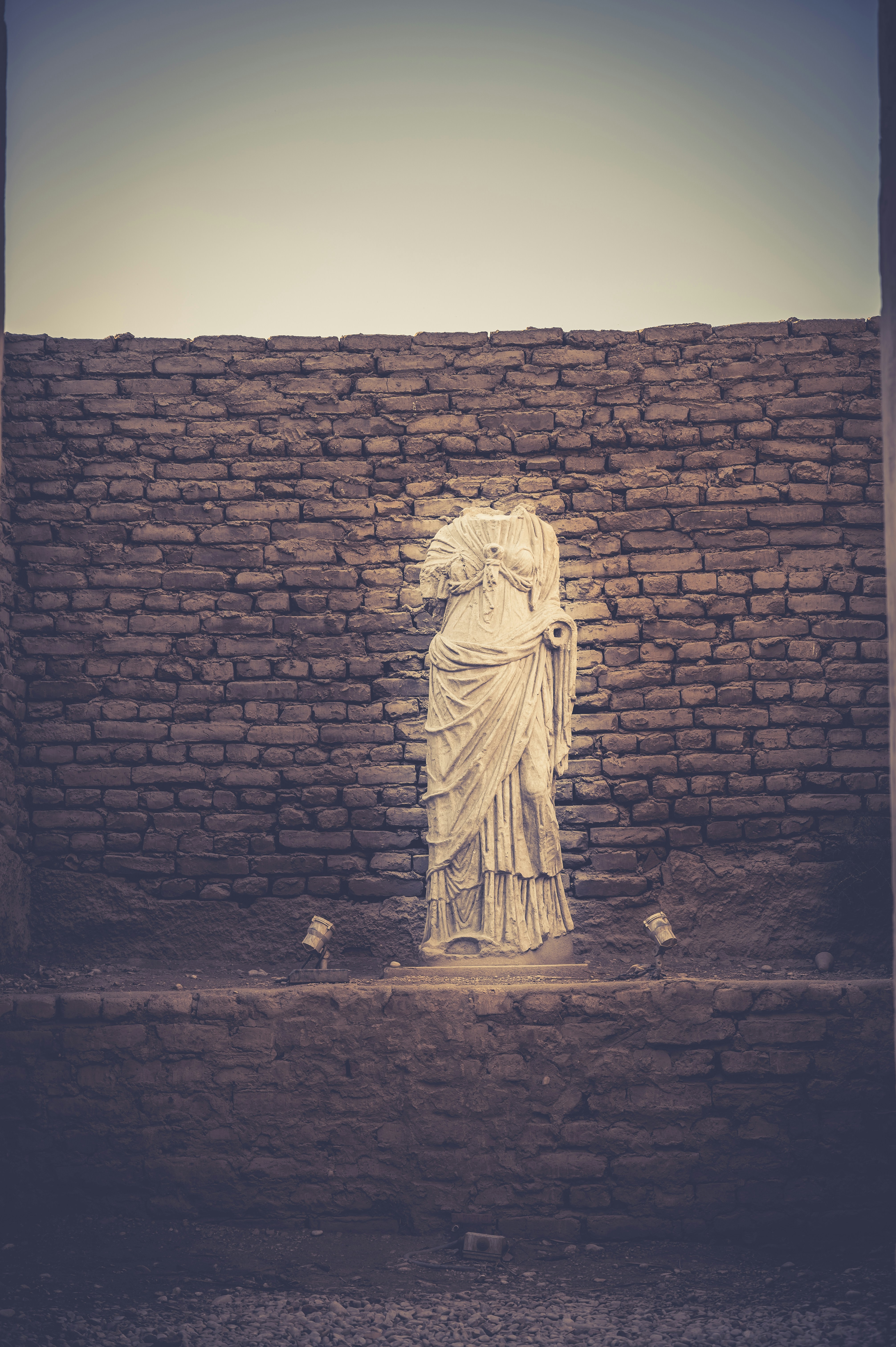 The Veiled Figure Standing Guard Before Weathered Bricks at Twilight