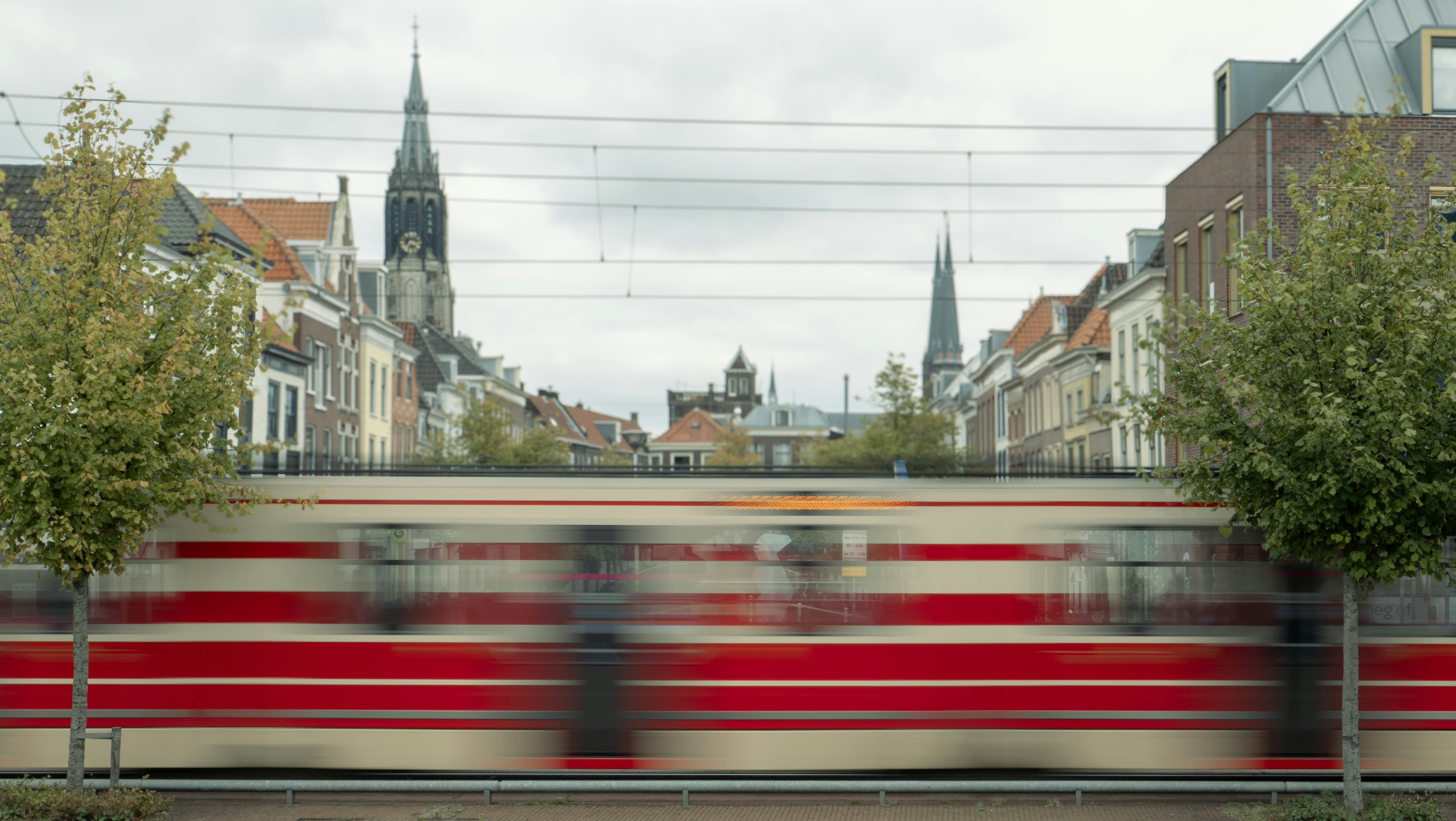 A red and white train traveling past tall buildings photo – Free Delft ...