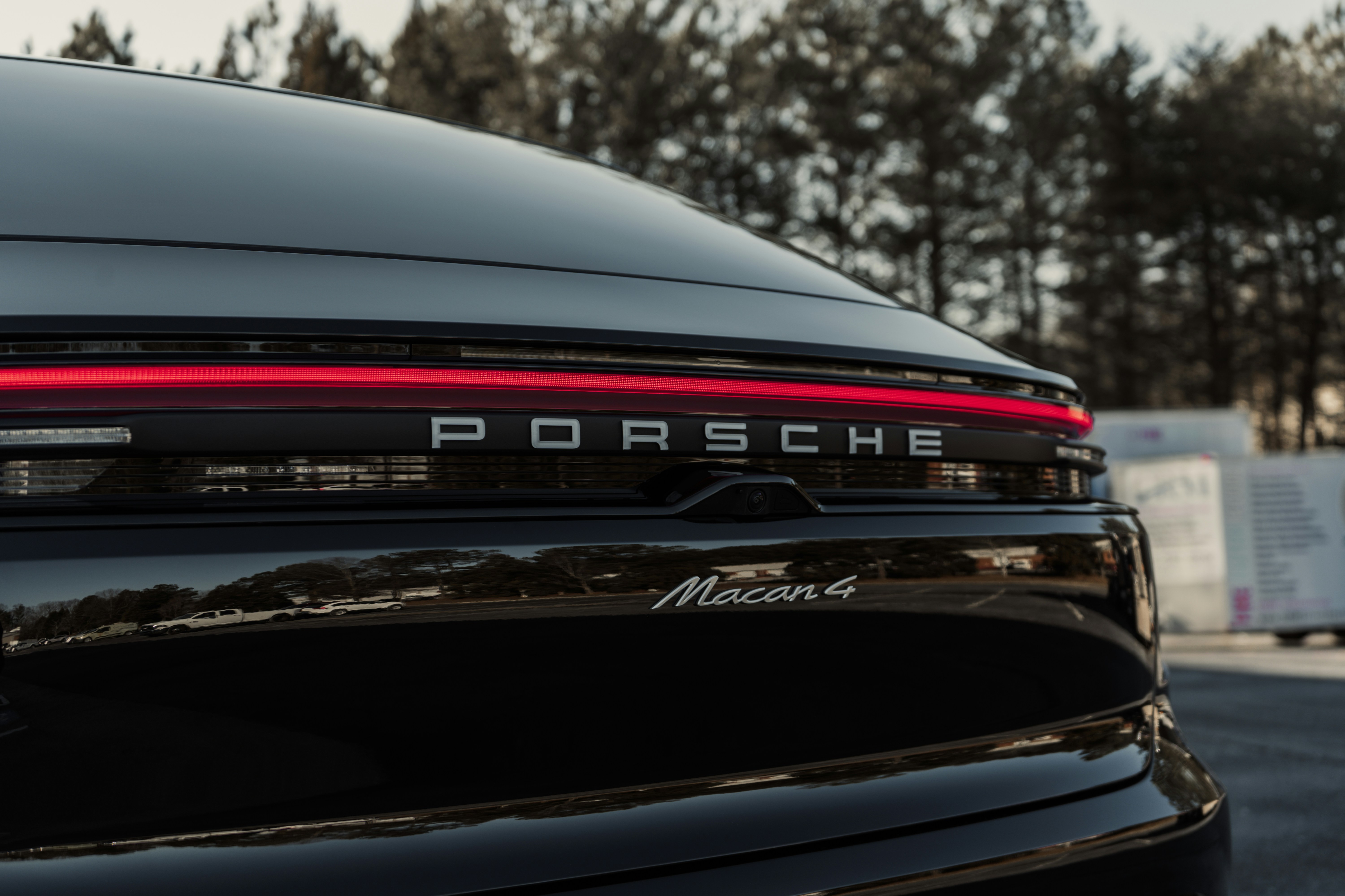 Rearview of a Porsche Taycan with 'Nacan' badge catching evening light