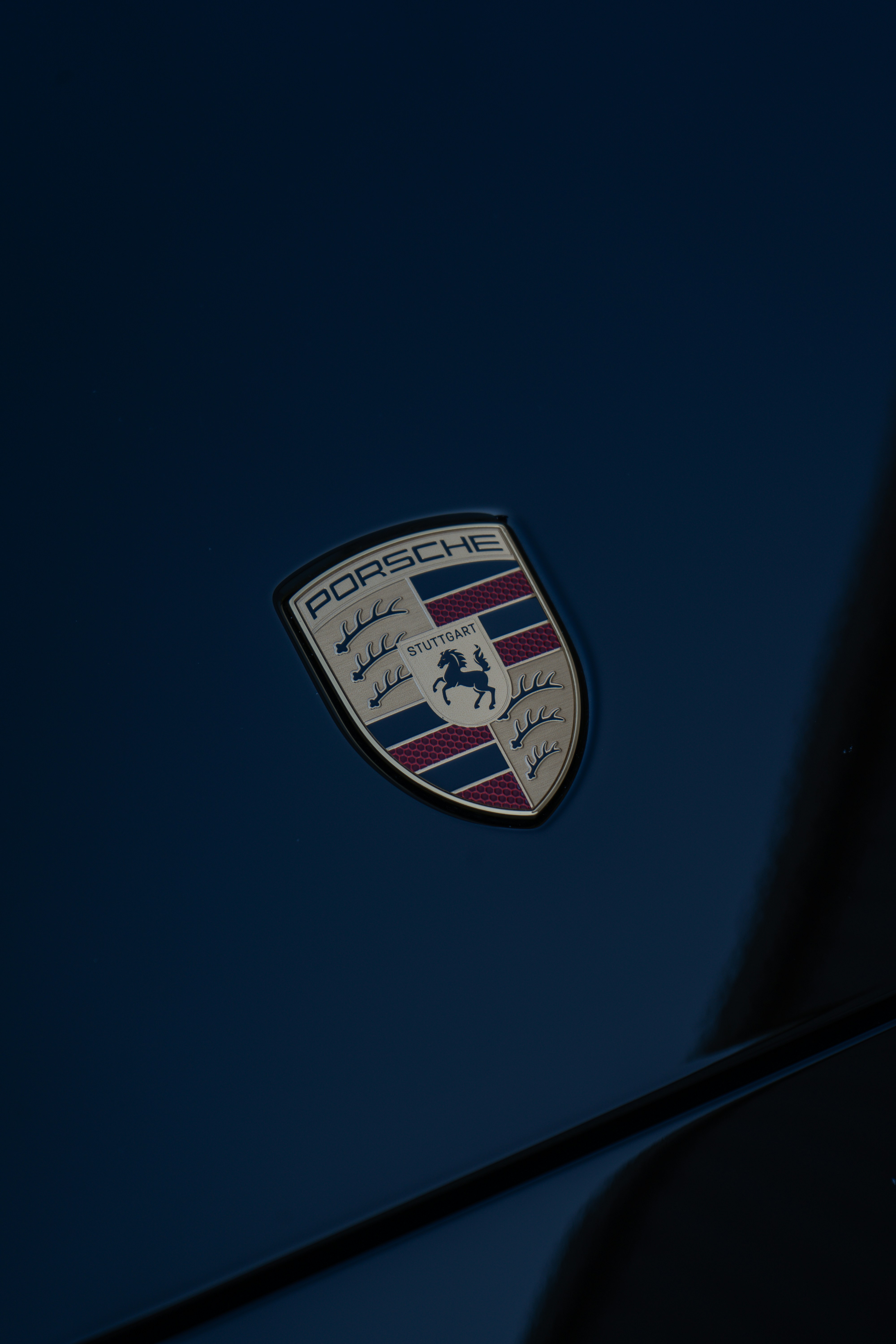 Midnight Crest on Velvet Blue: Porsche Emblem in Quiet Focus