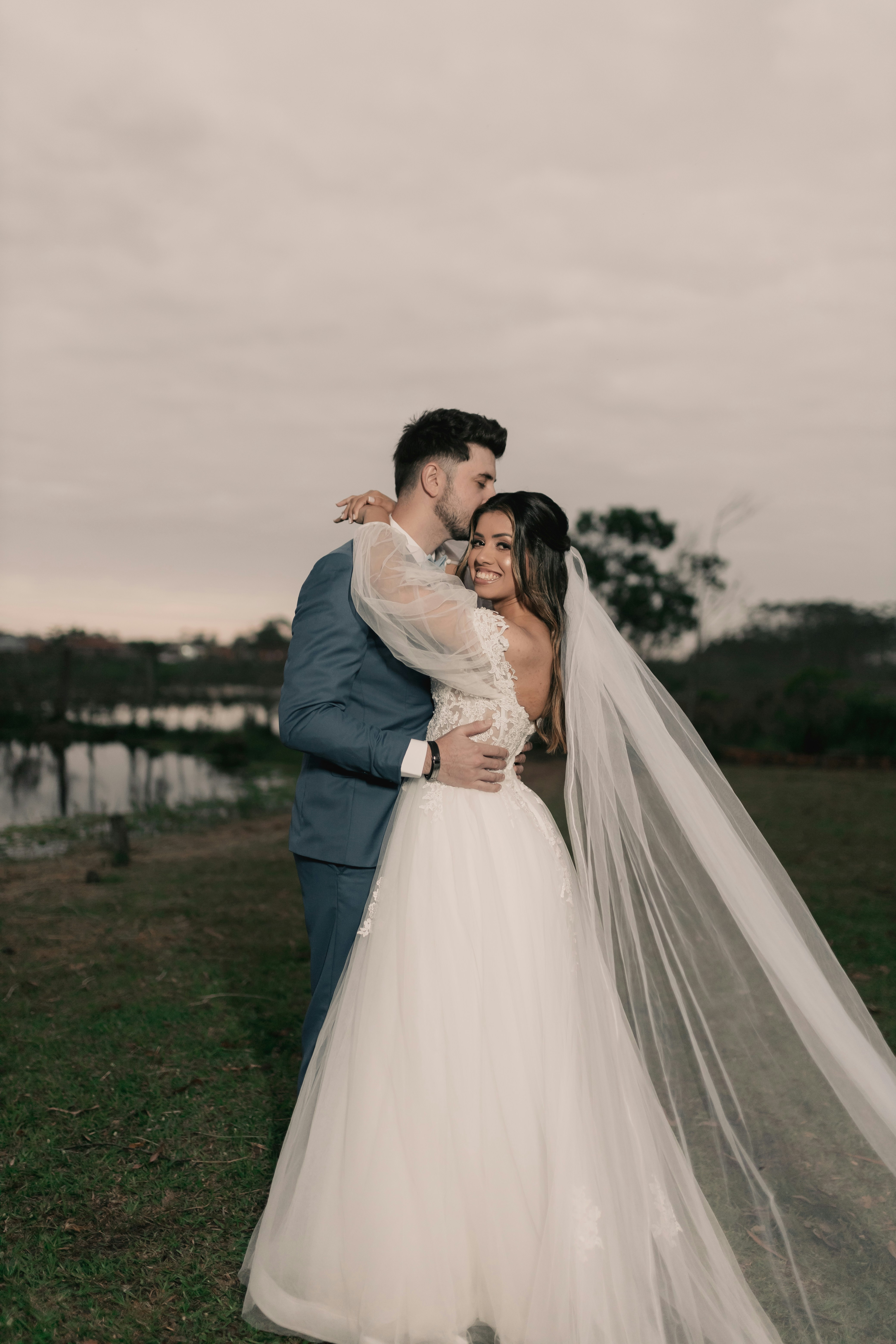 A bride and groom standing in front of a lake photo – Free Dress Image ...