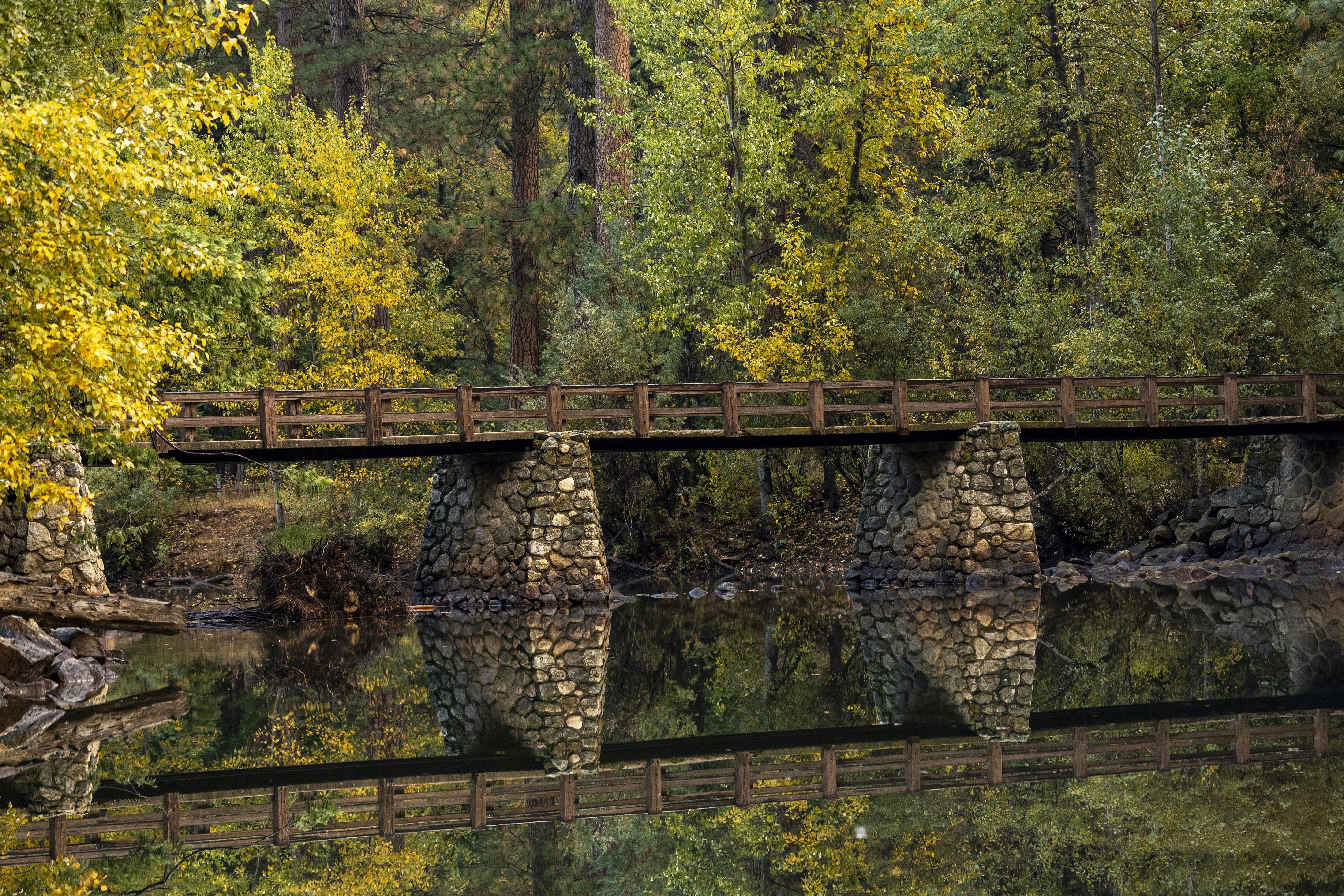 Autumn Span: Wooden Bridge Framed by a Velvet River Reflection
