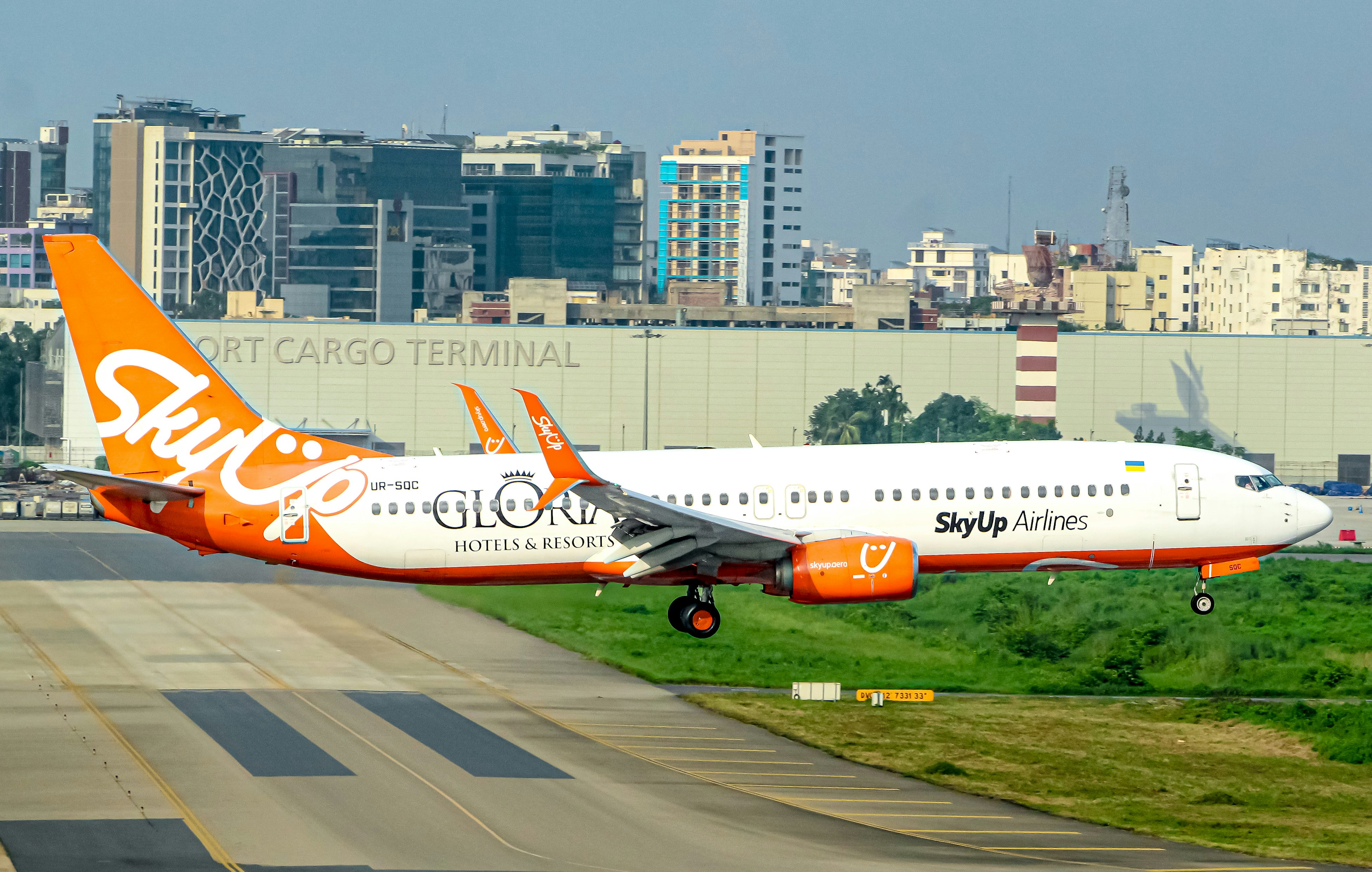 An orange and white jet airliner taking off from an airport runway ...