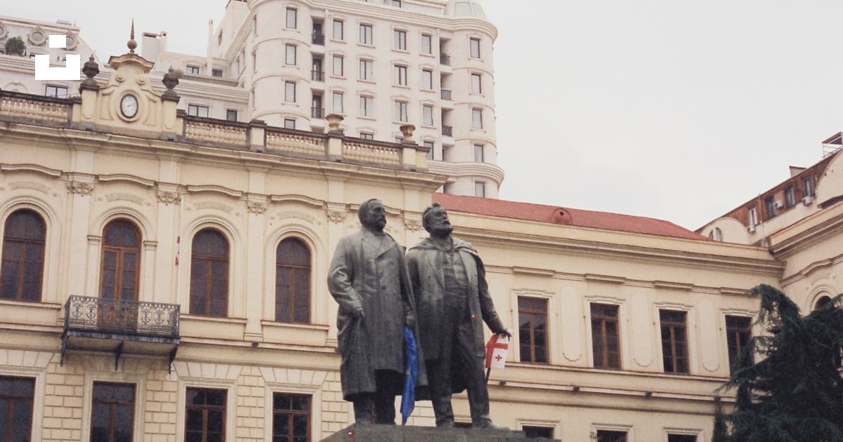 Una Estatua De Dos Hombres Frente A Un Edificio Foto Imagen De