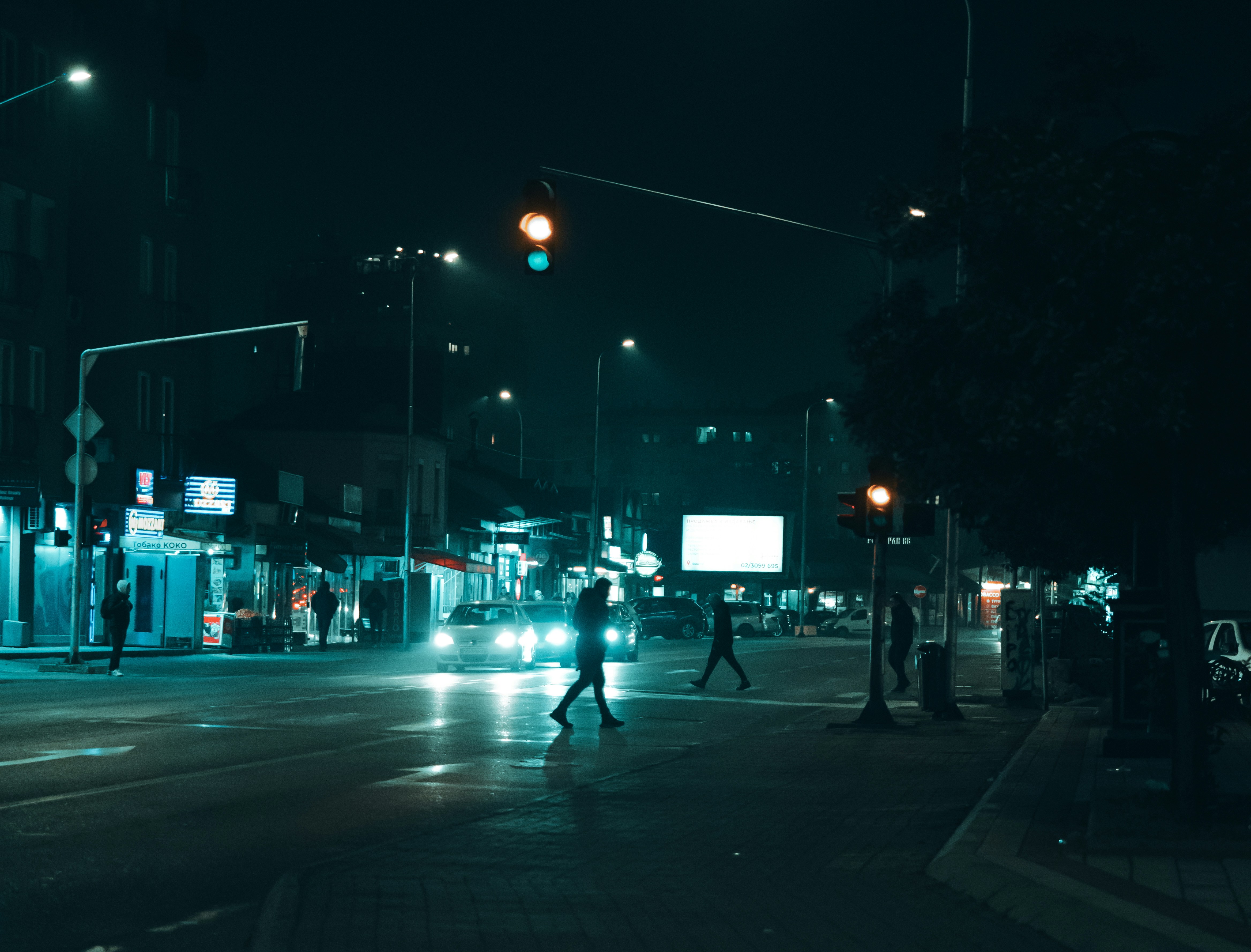A city street at night with people crossing the street photo – Free ...