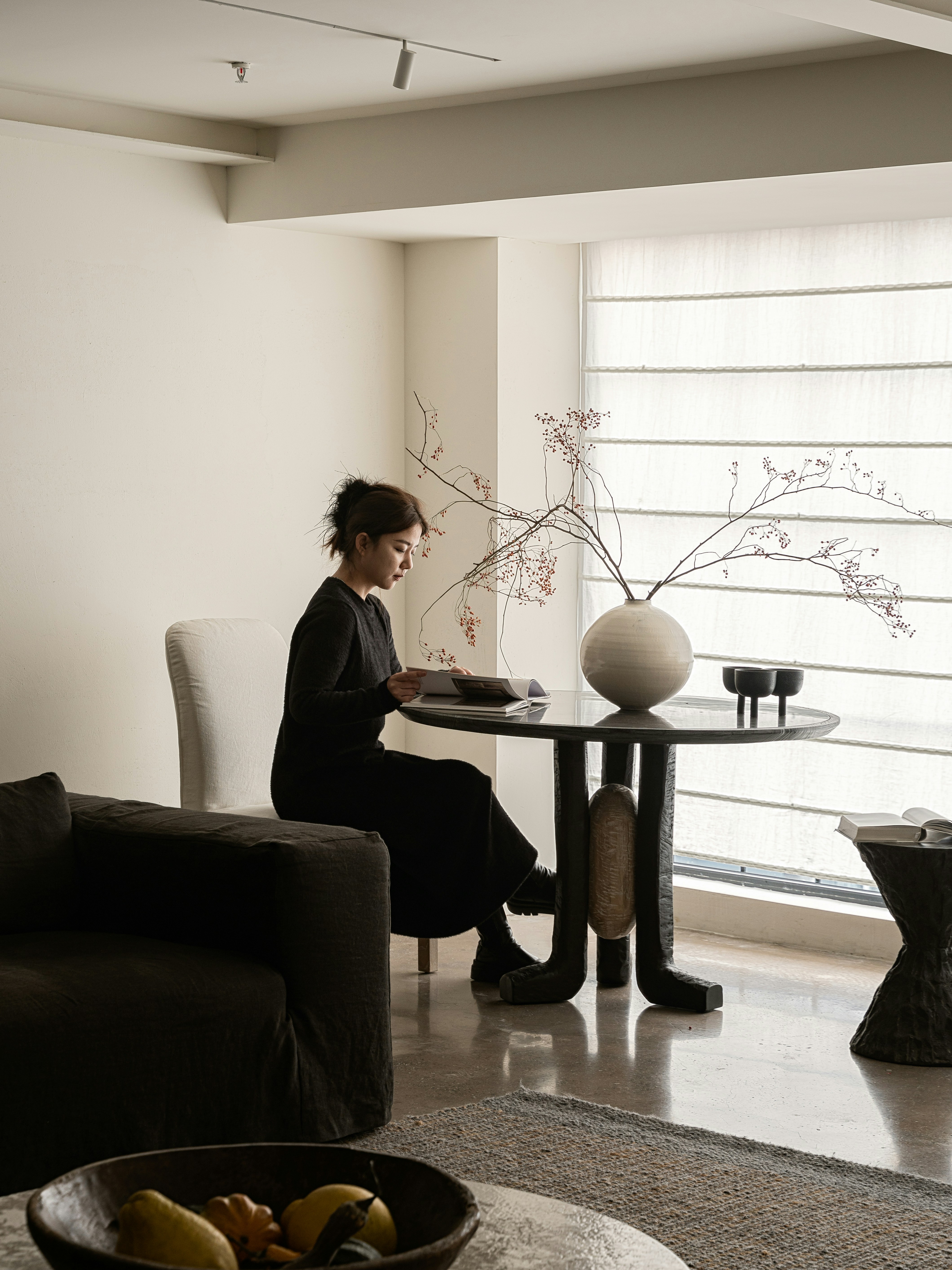 A woman sitting at a table in a living room photo – Free Woman Image on ...