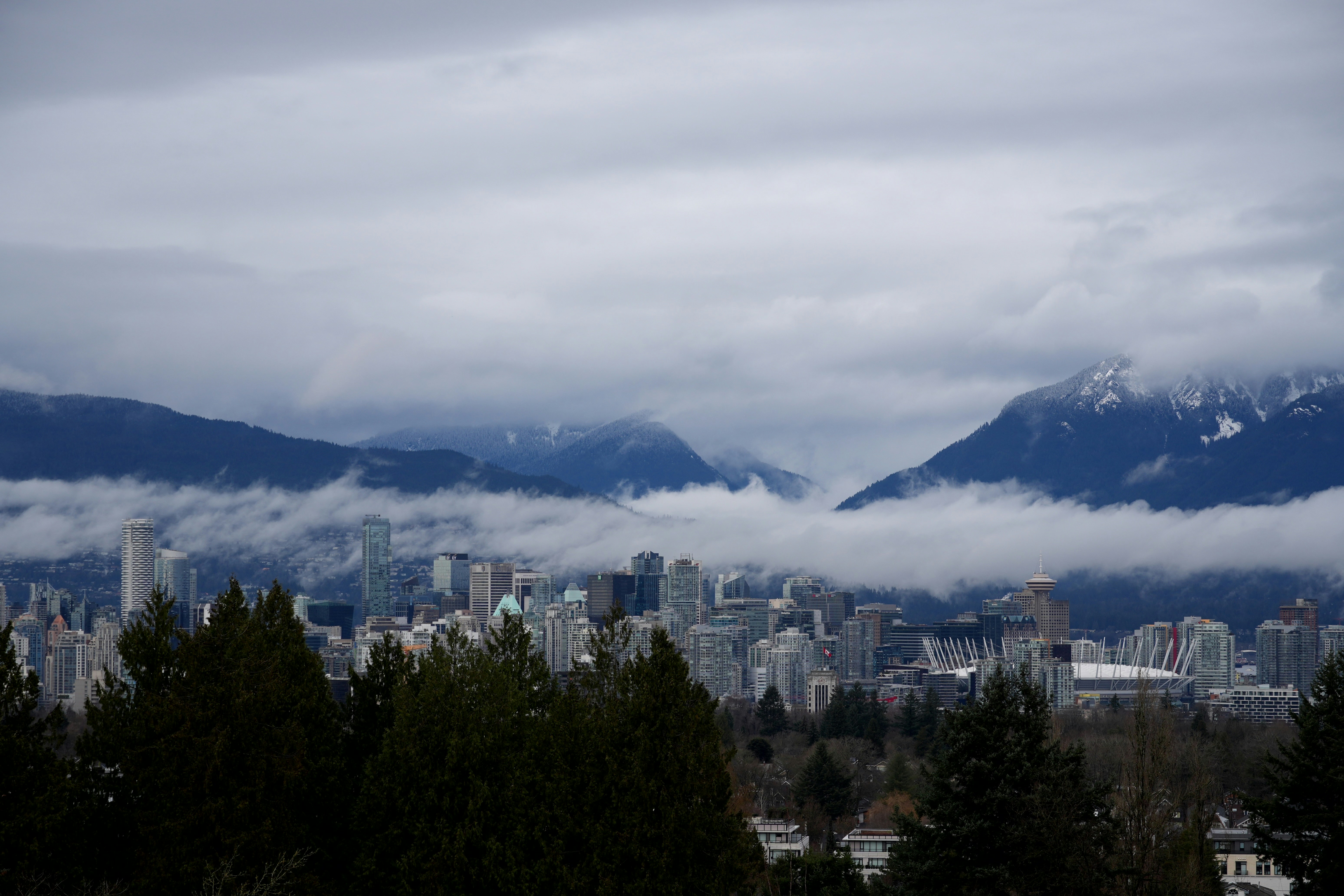 Cityscape Beneath a Veil: Snow-Kissed Peaks and Cloud-Locked Skyline