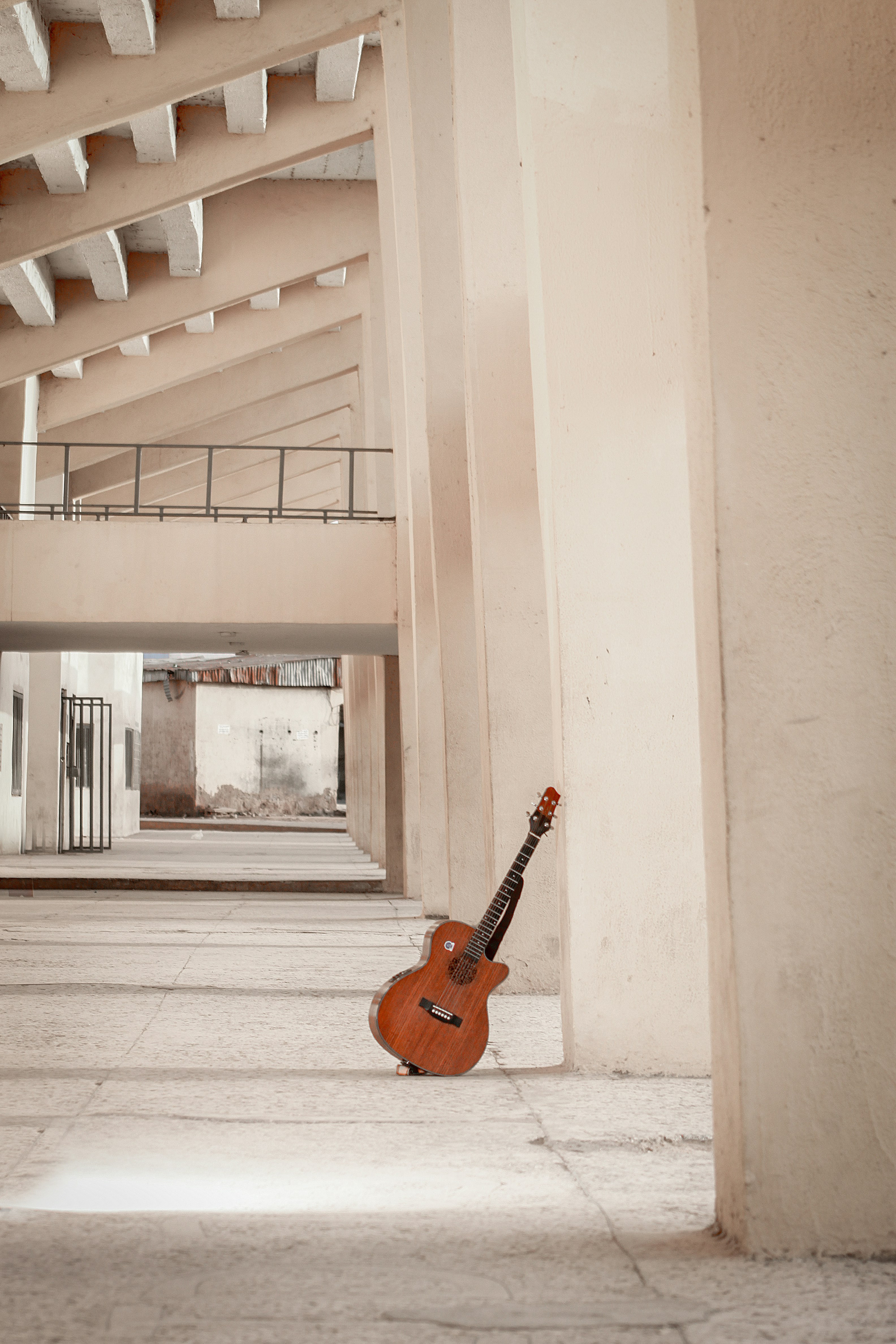 Guitar by the Sunlit Arcade: Warm Wood Against Cold Concrete