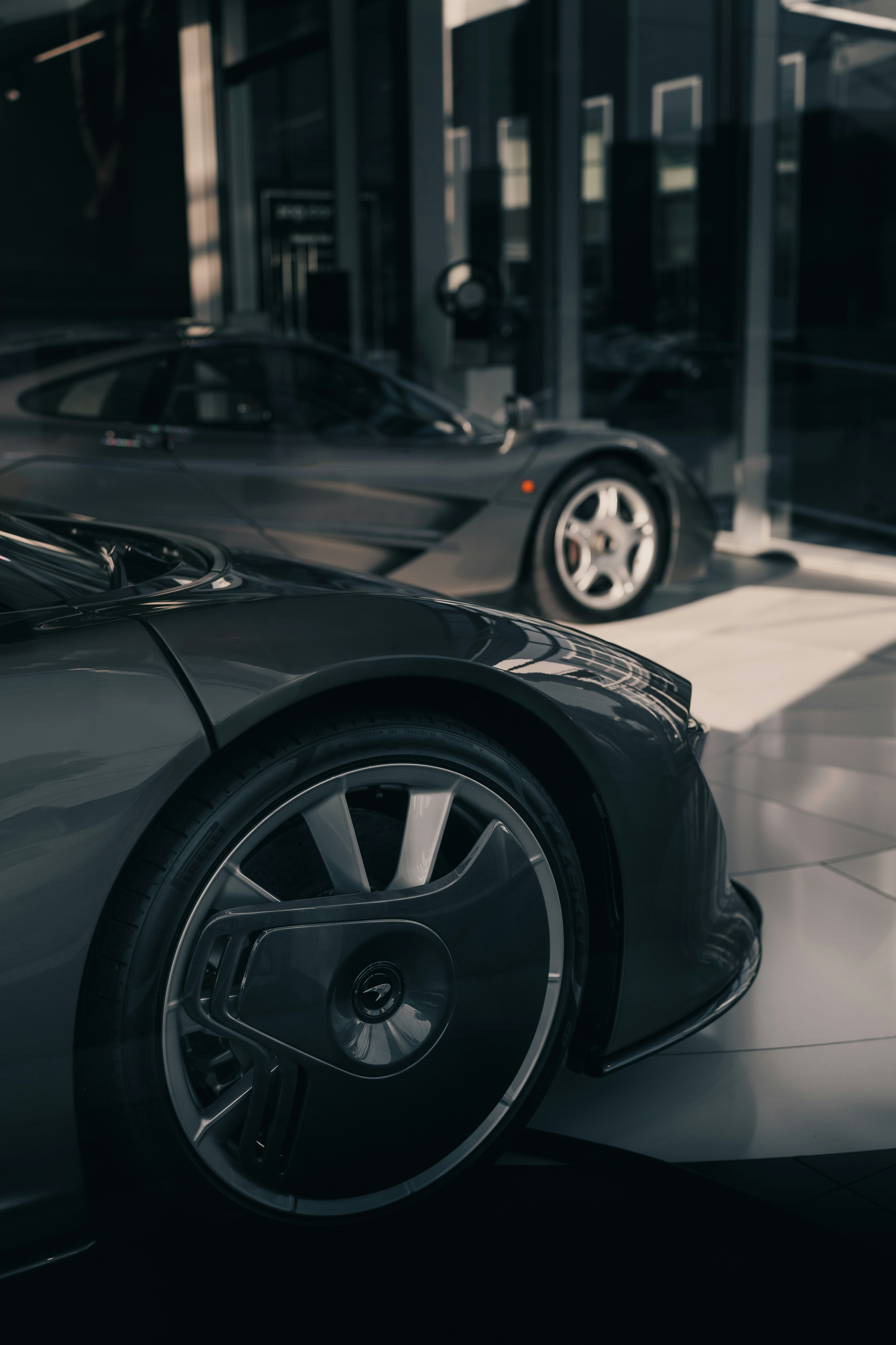 Luxury sports cars in a showroom with sleek lines and reflective surfaces under ambient light.