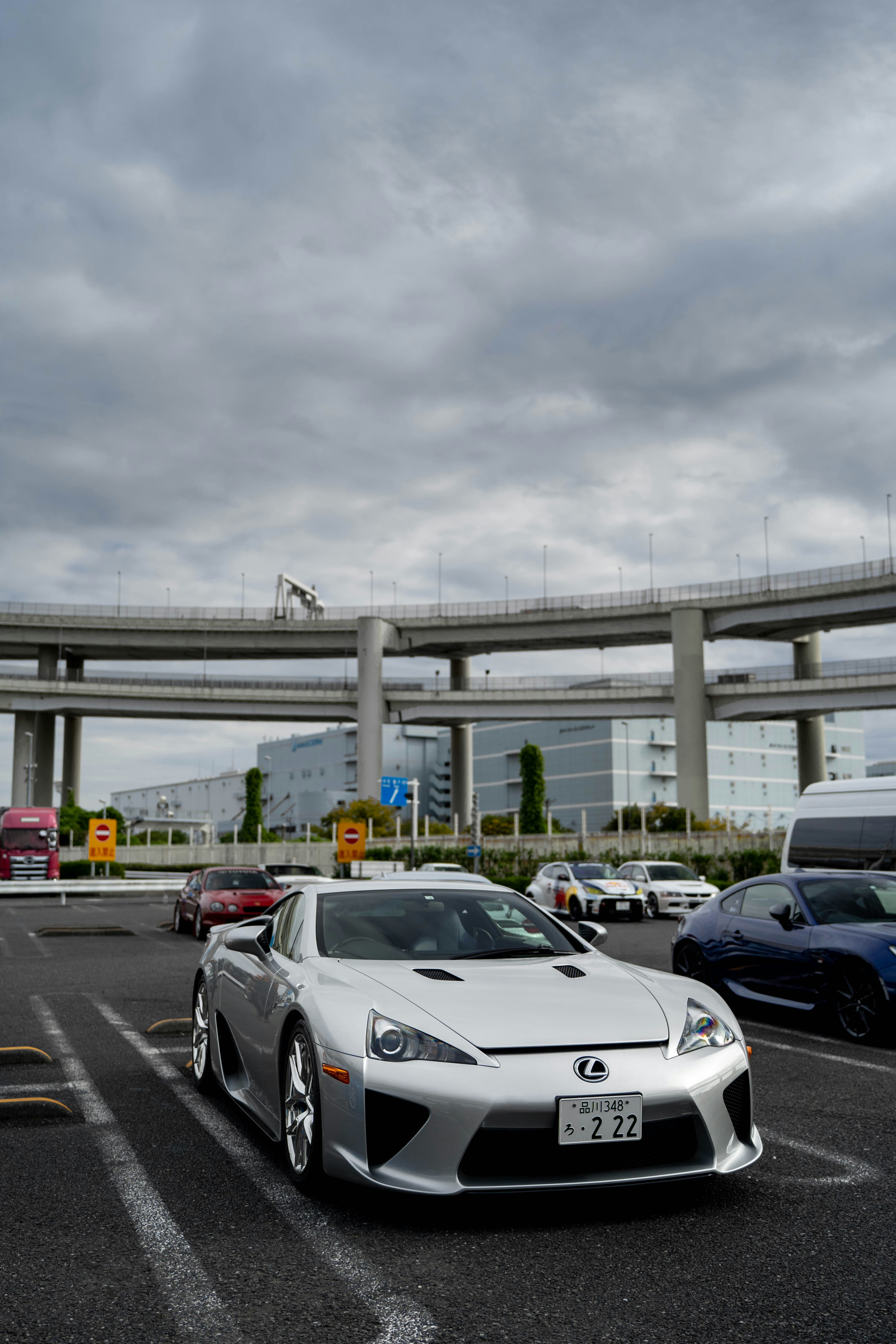 Chrome on Concrete: Front View of a Silver Lexus in a Parking Lot Beneath Elevated Highways