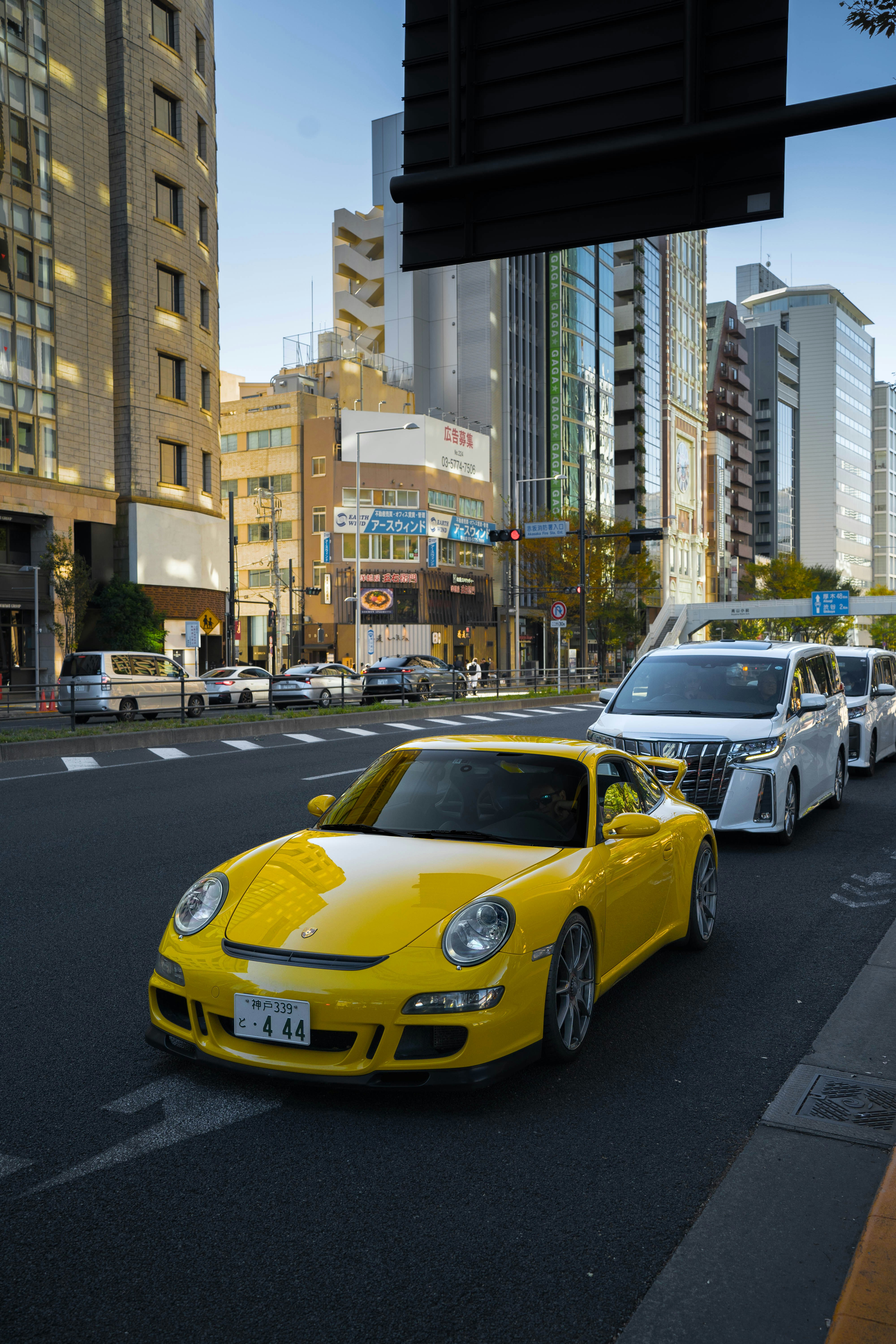 A yellow car driving down a street next to tall buildings photo – Free ...